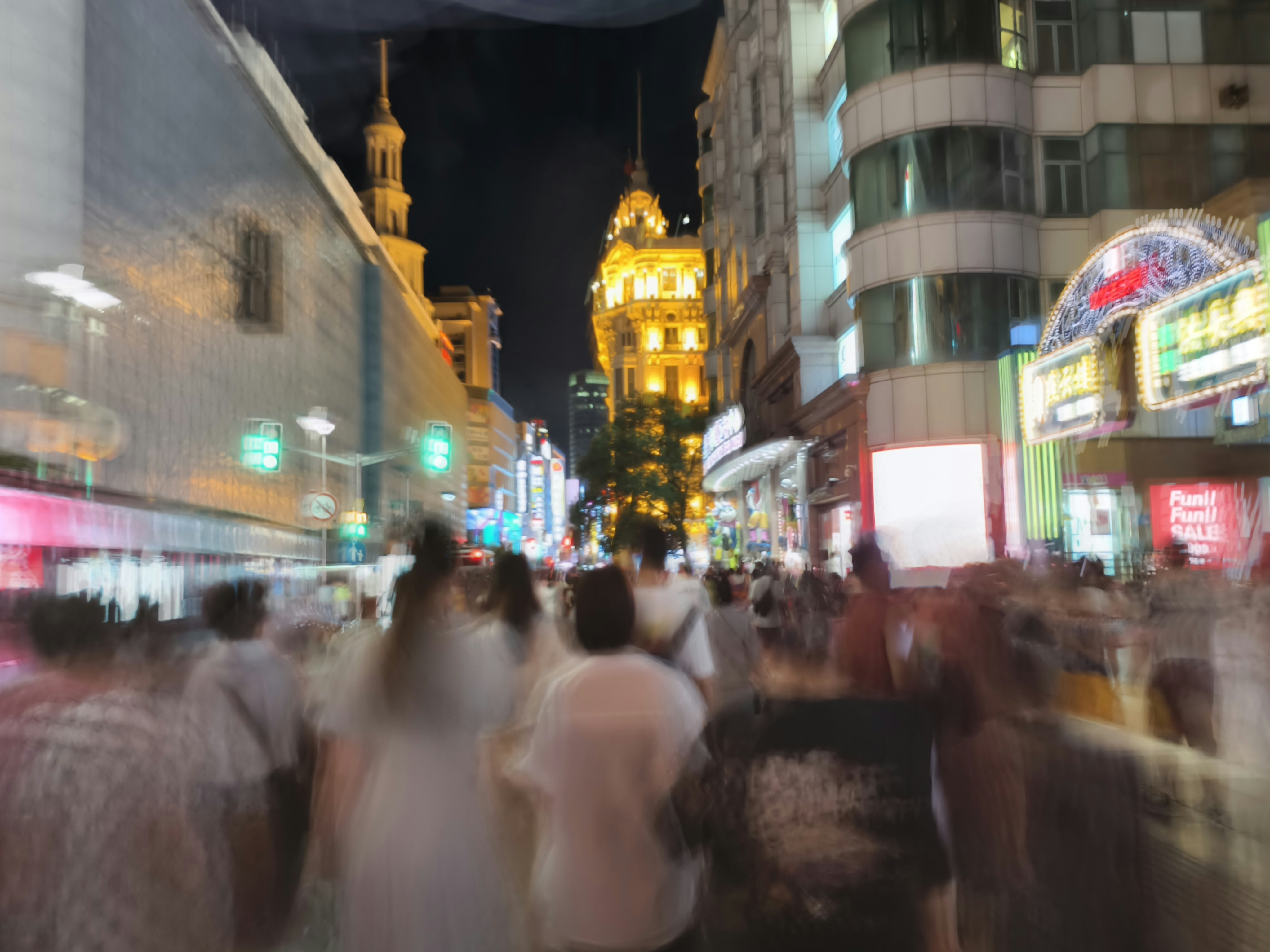 Blurred crowd walking along a neon-lit urban street at night.