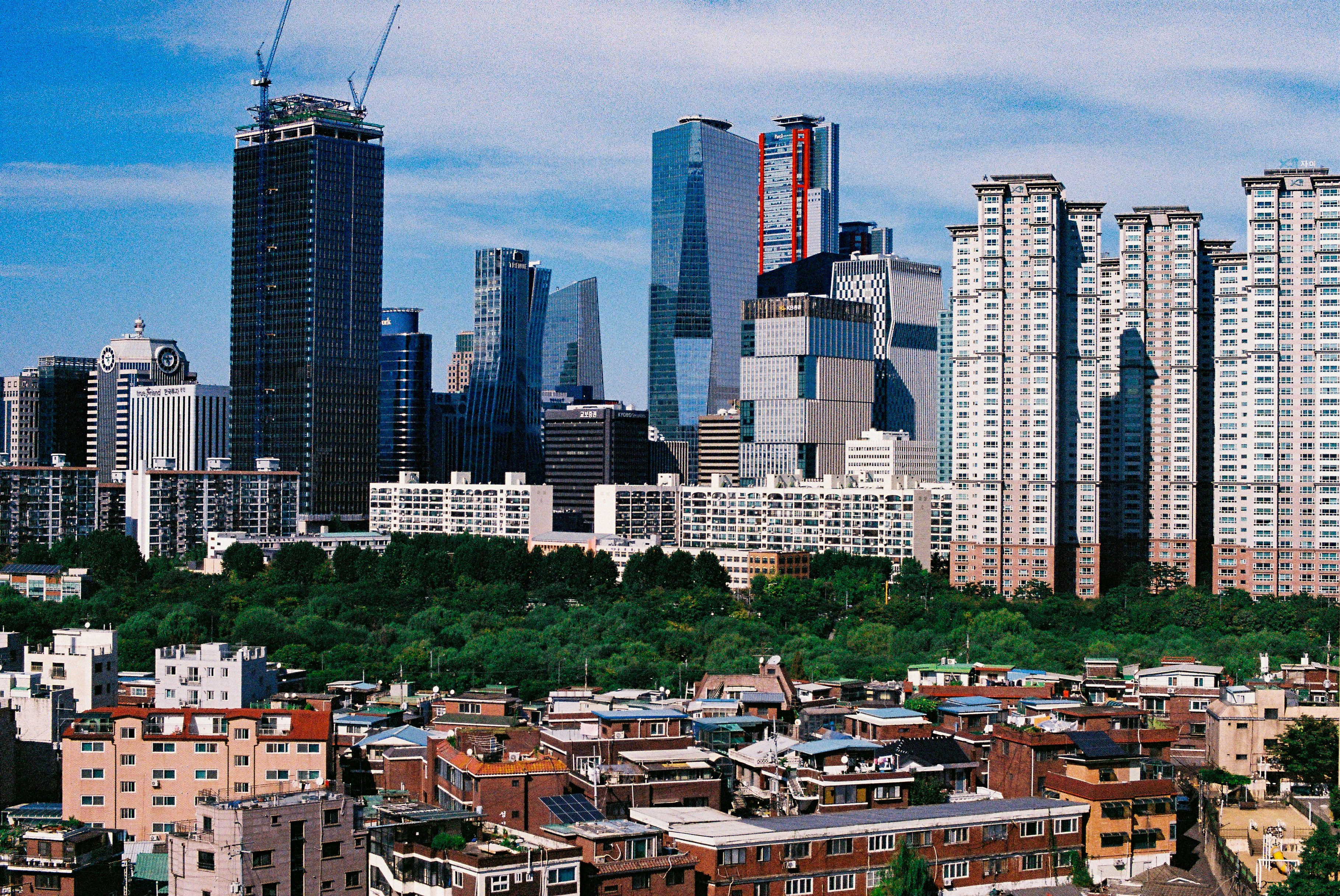 Modern skyscrapers rise behind a dense array of older buildings under a clear blue sky.