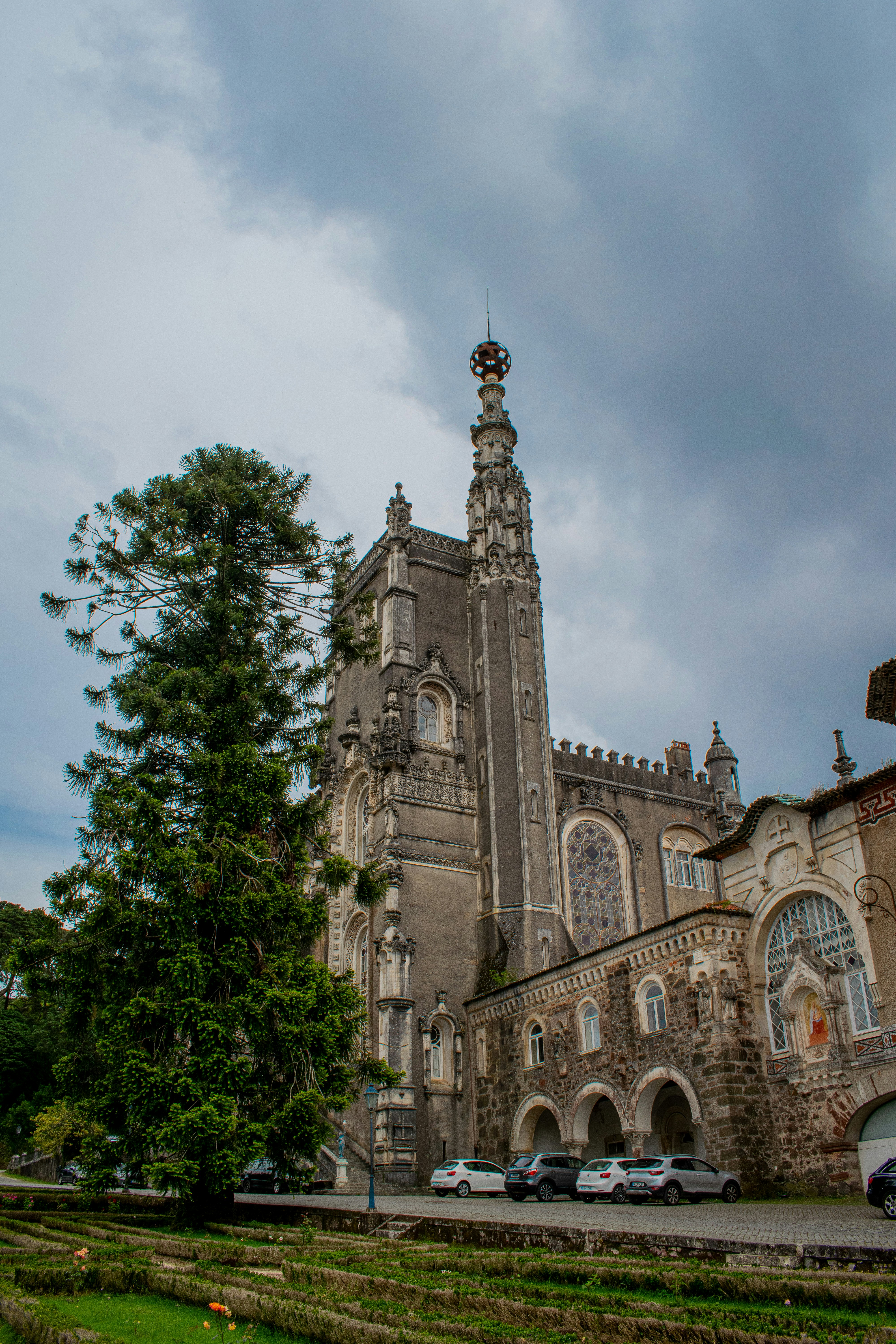 Towering Gothic Spire Framed by a Lone Tree Under a Cloudy Sky