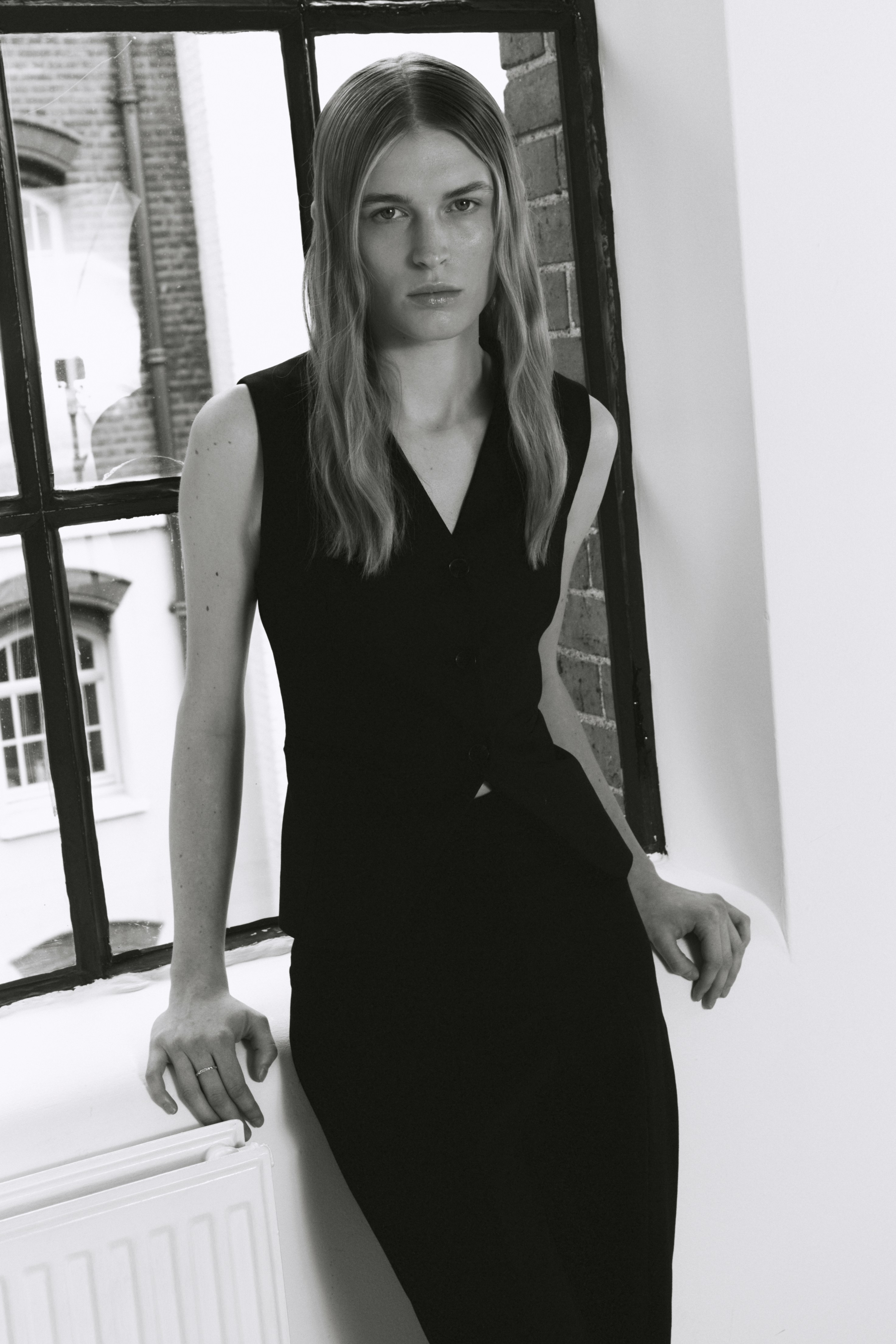 A woman in a black dress leaning against a window photo – Free ...