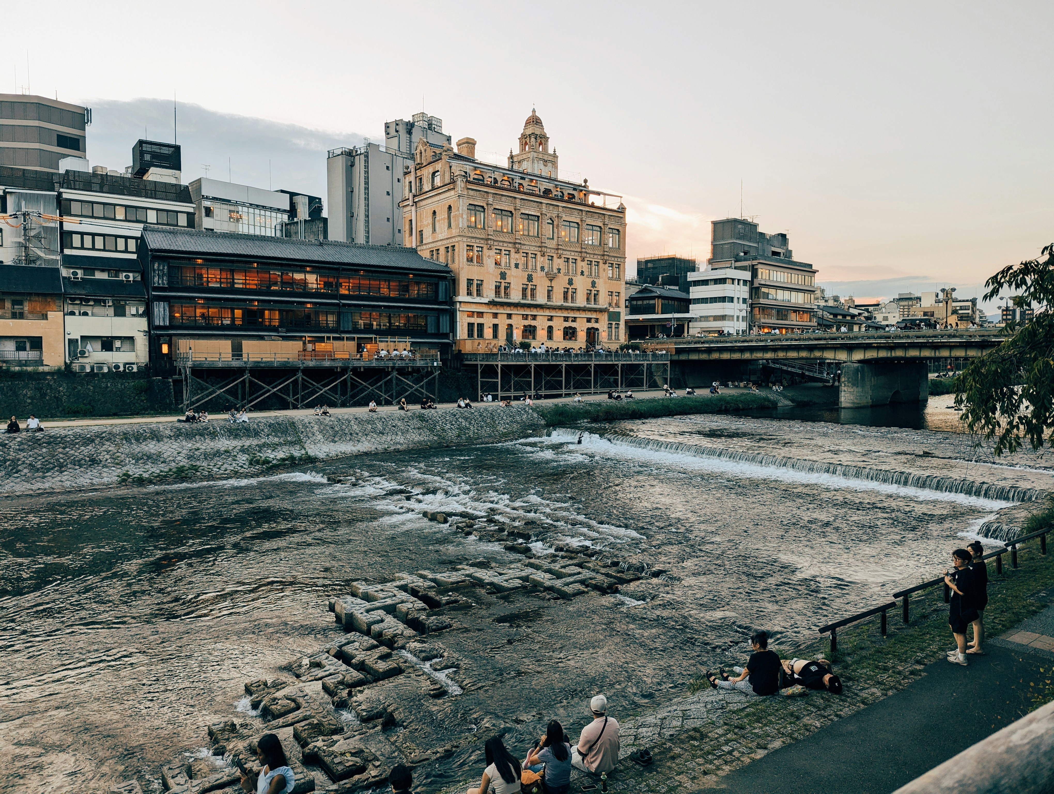 A group of people walking on a sidewalk next to a river photo – Free ...