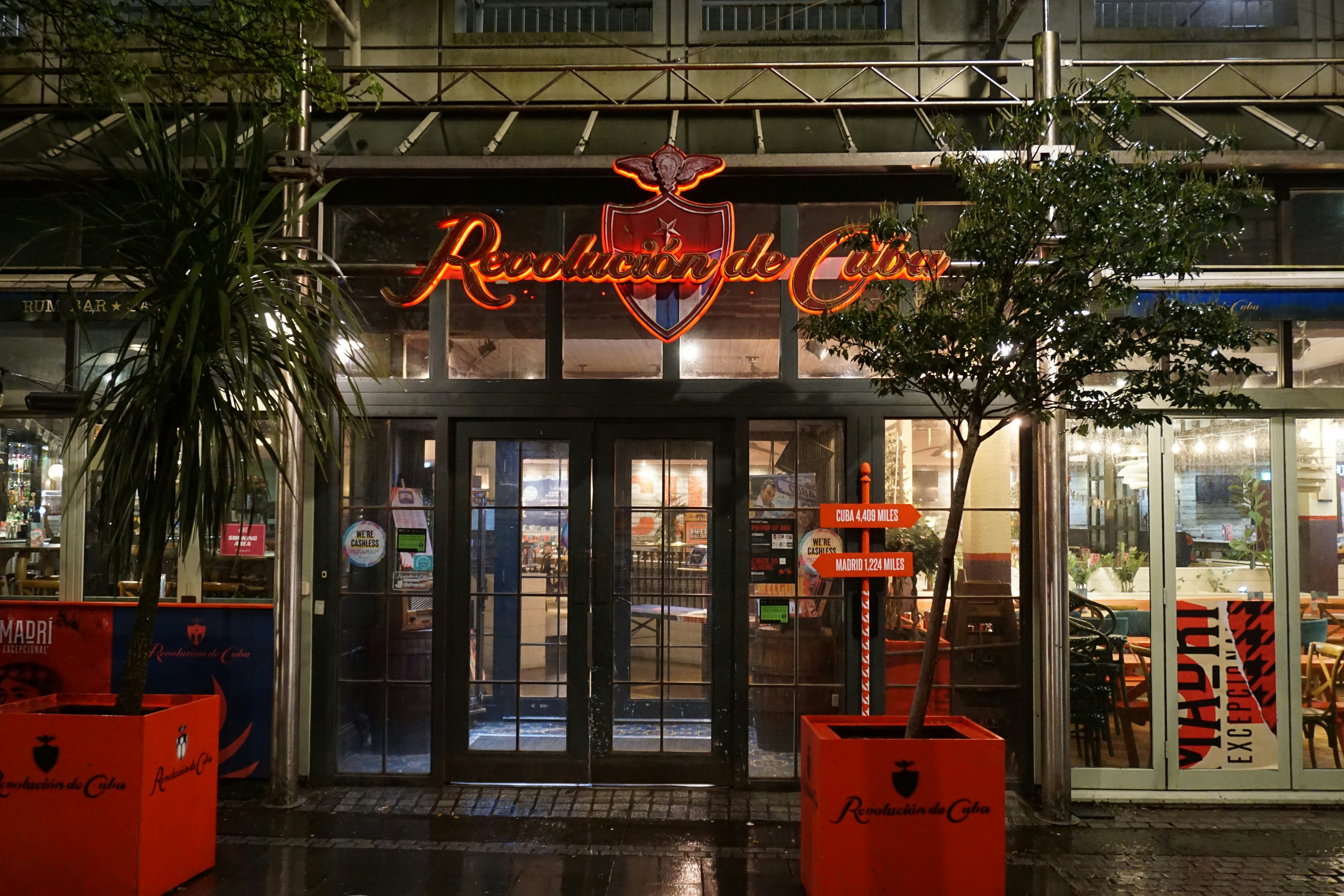 Restaurant entrance illuminated by vibrant neon signage at night.