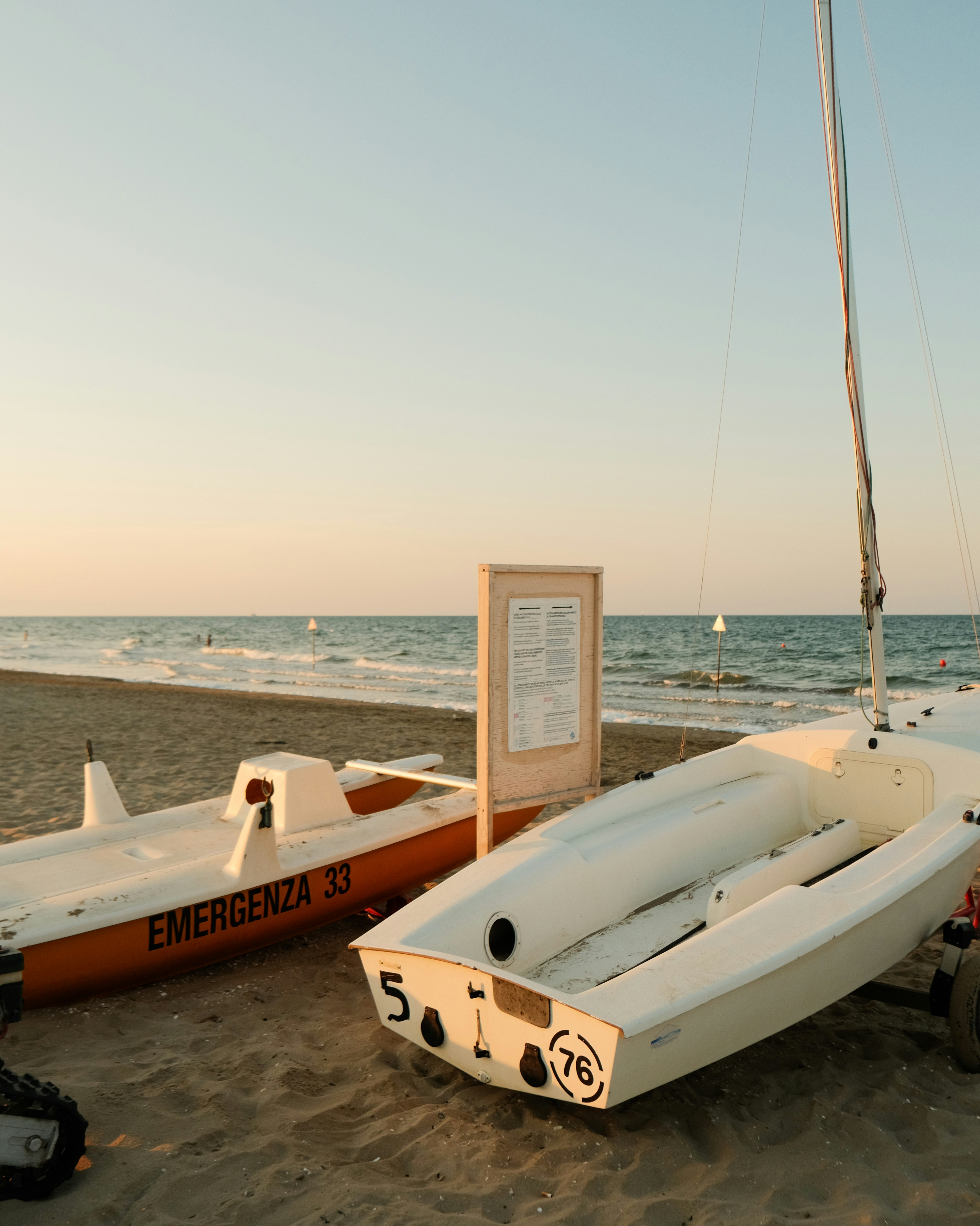 Dinghies at Dusk: A Signboard Stands Watch by the Quiet Sea