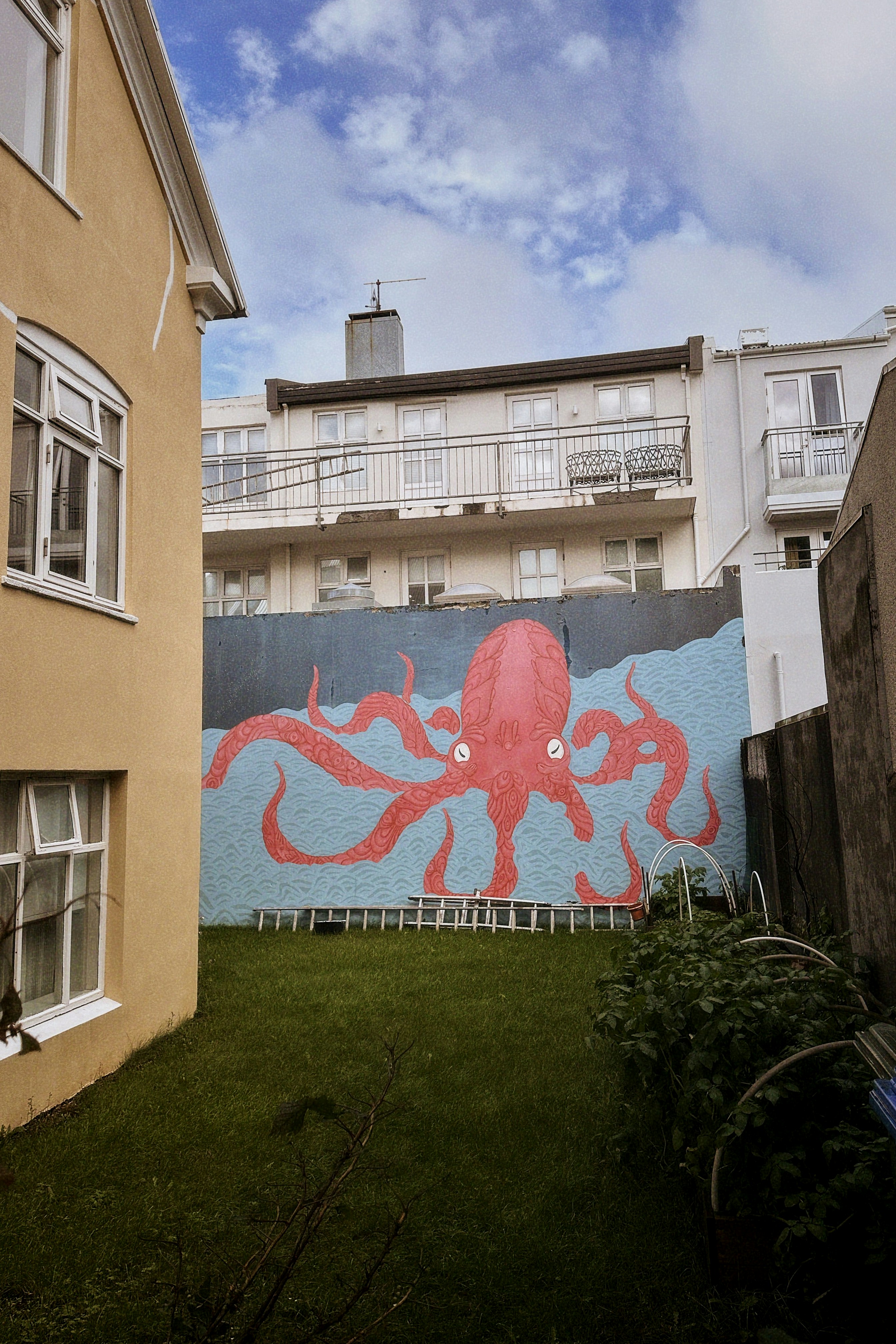 Red Octopus Mural Anchors a Sunlit Courtyard Between Fortified Facades