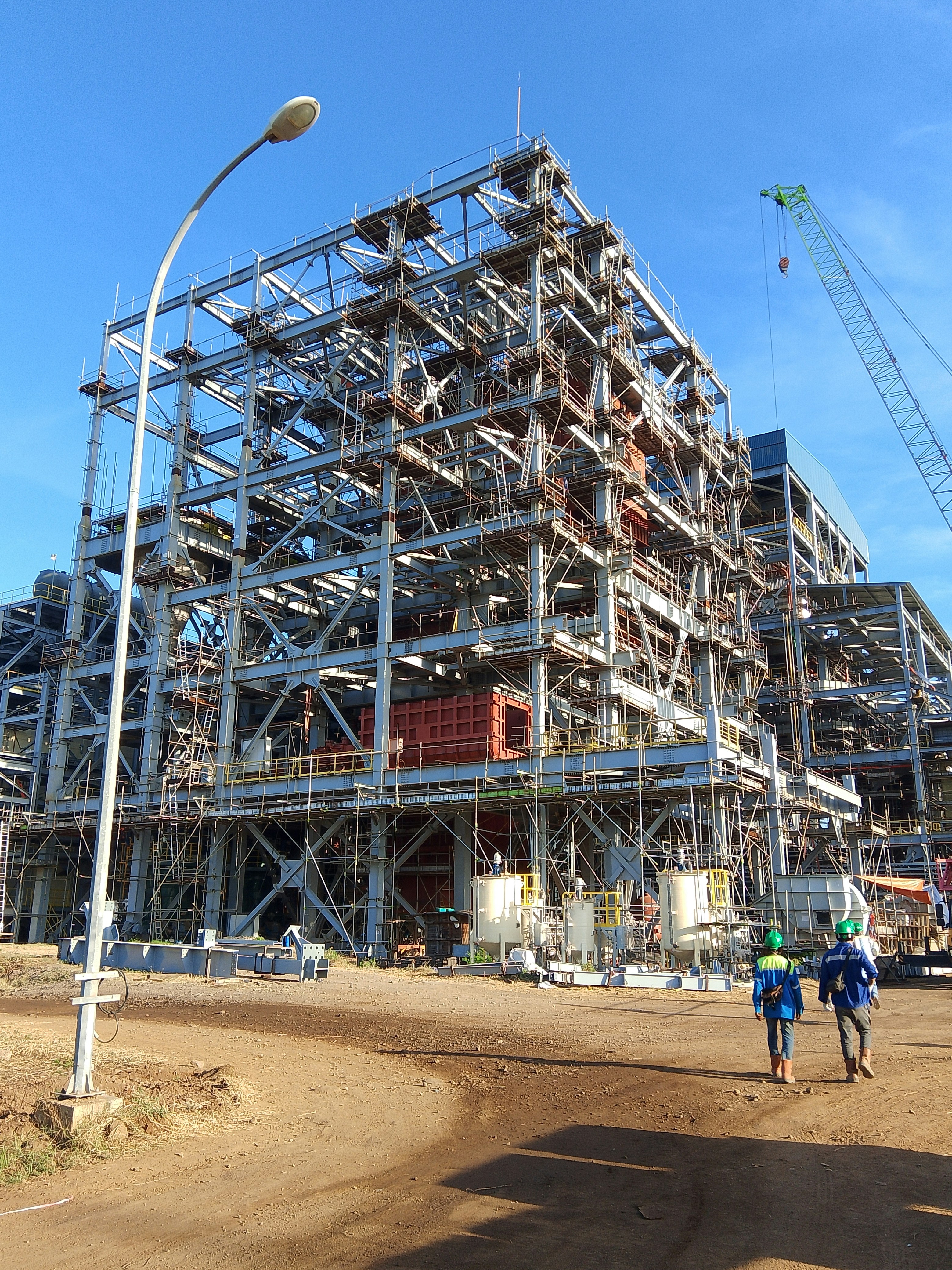 A large building under construction on a dirt road
