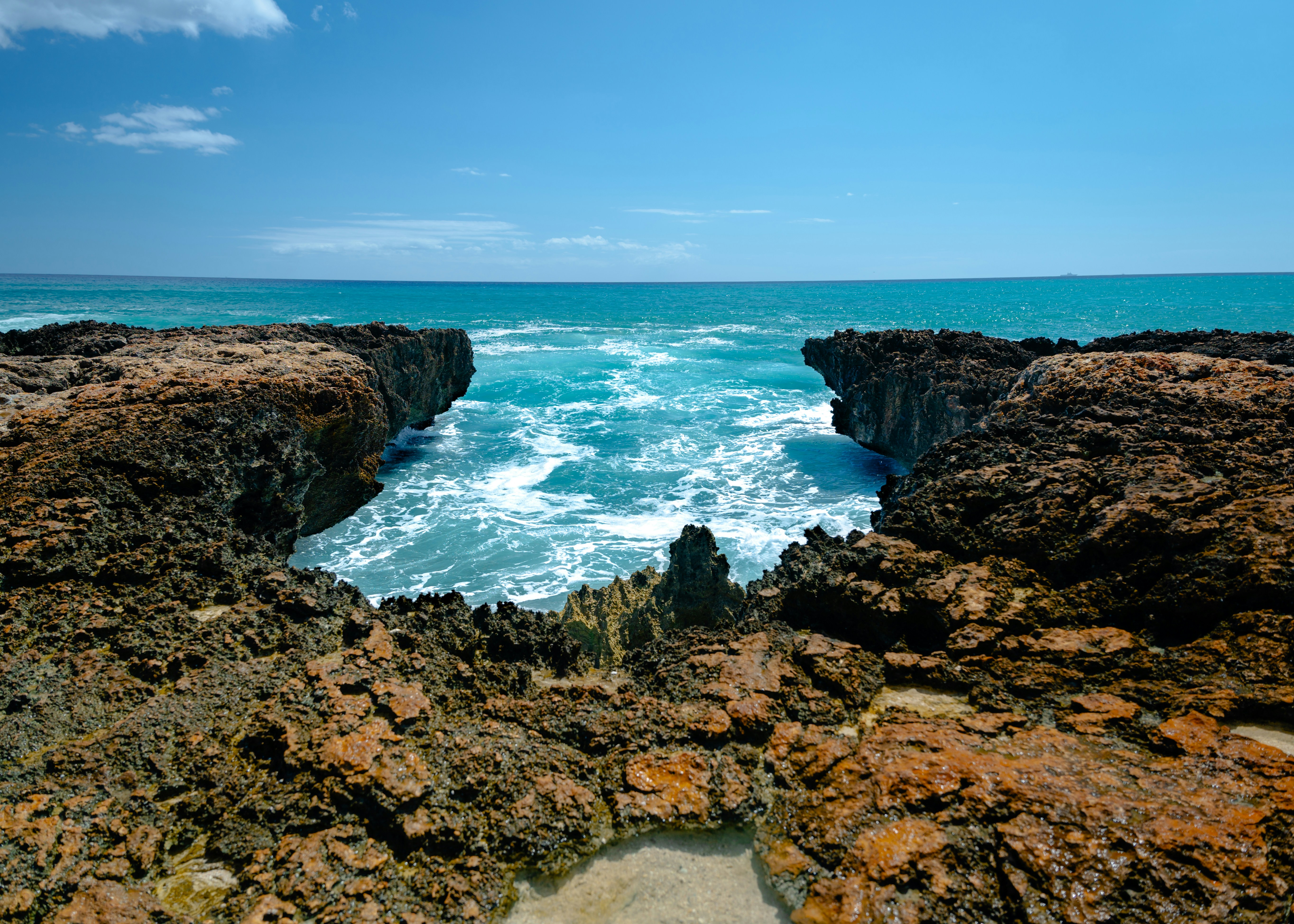 Rocky coastline framing a vibrant blue ocean under a clear sky.