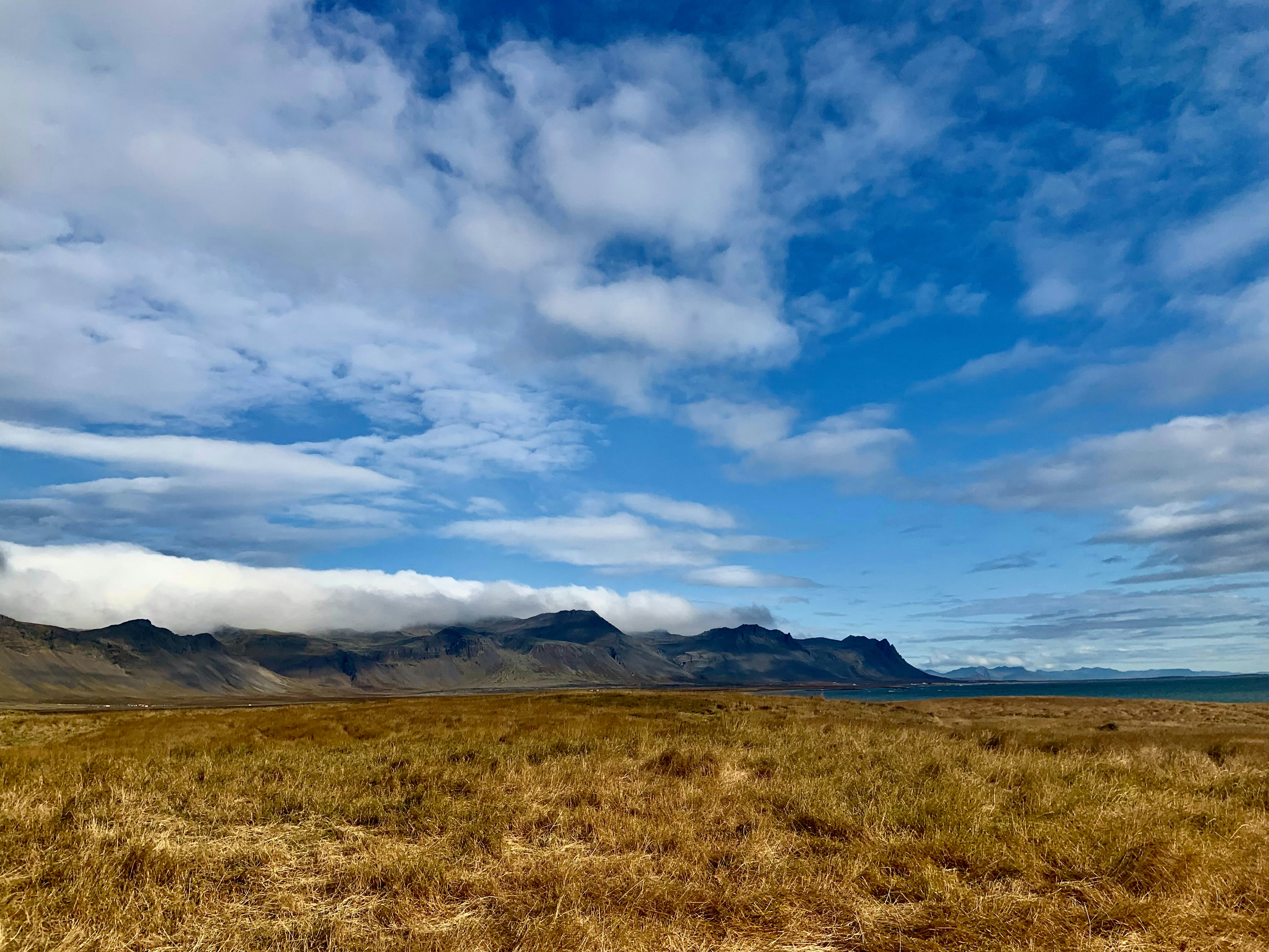 A field with mountains in the distance under a cloudy skyJustin Lindemann