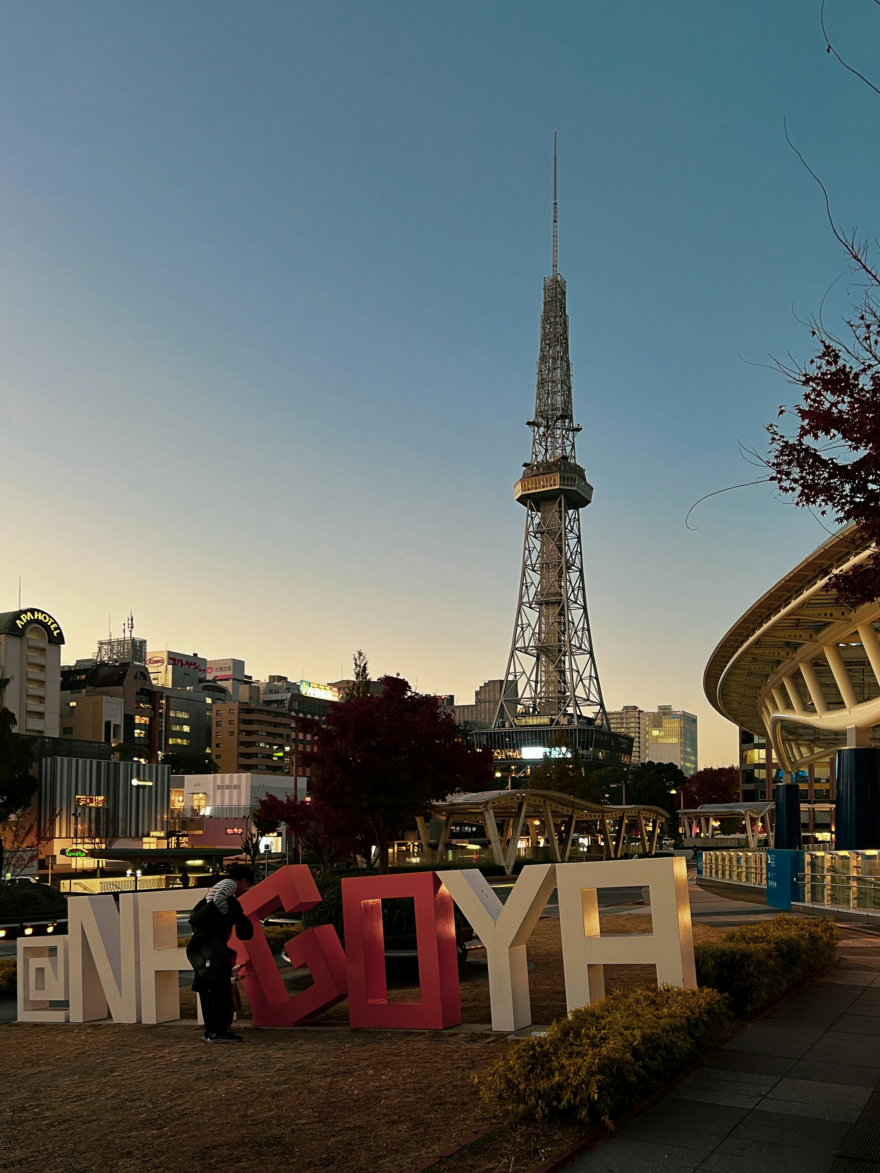 @NAGOYA sign in the foreground with Nagoya Tower and city skyline under a twilight sky.
