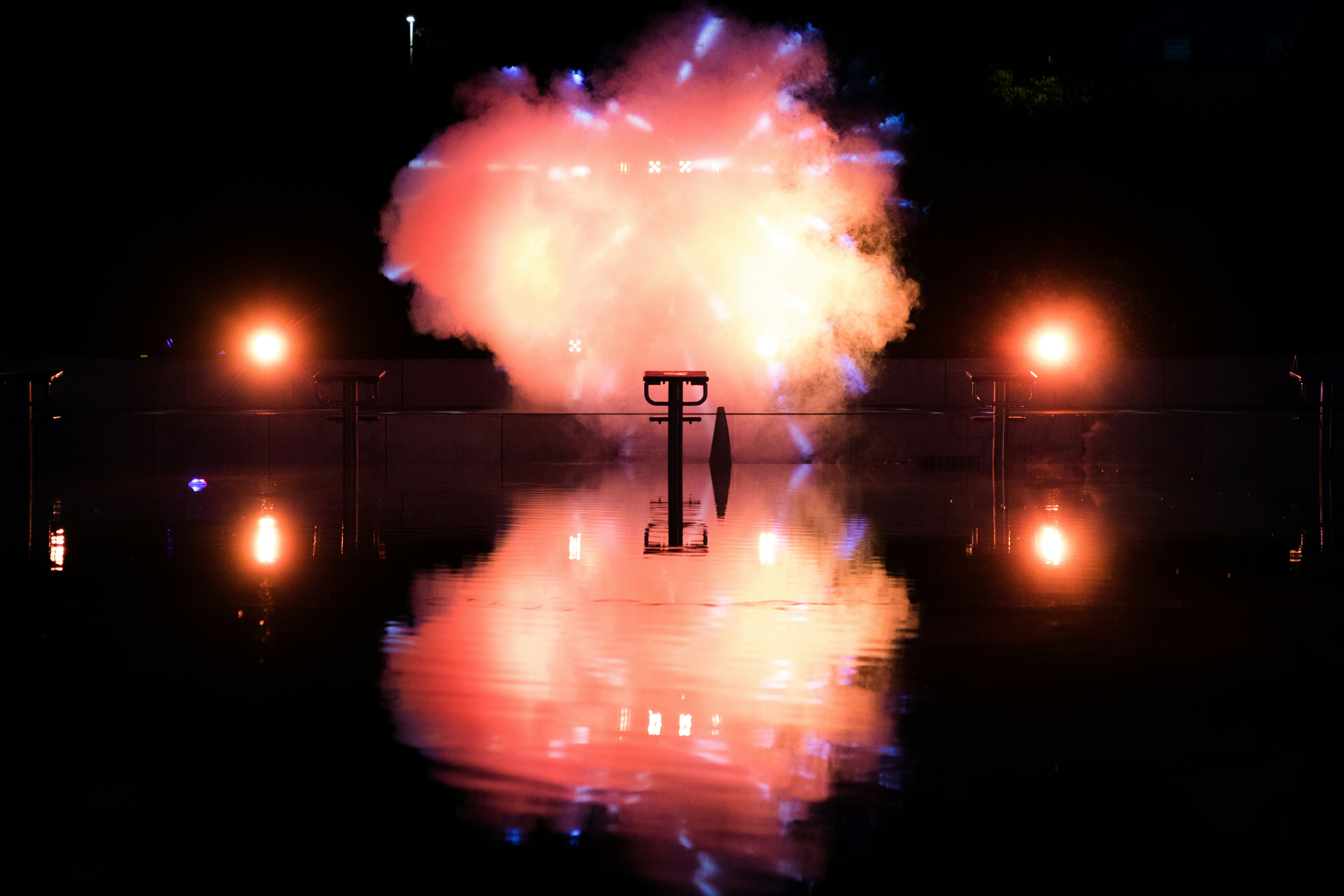 Centerstage Pyro Mirage: A Night Burst and Glassy Reflection on Still Water