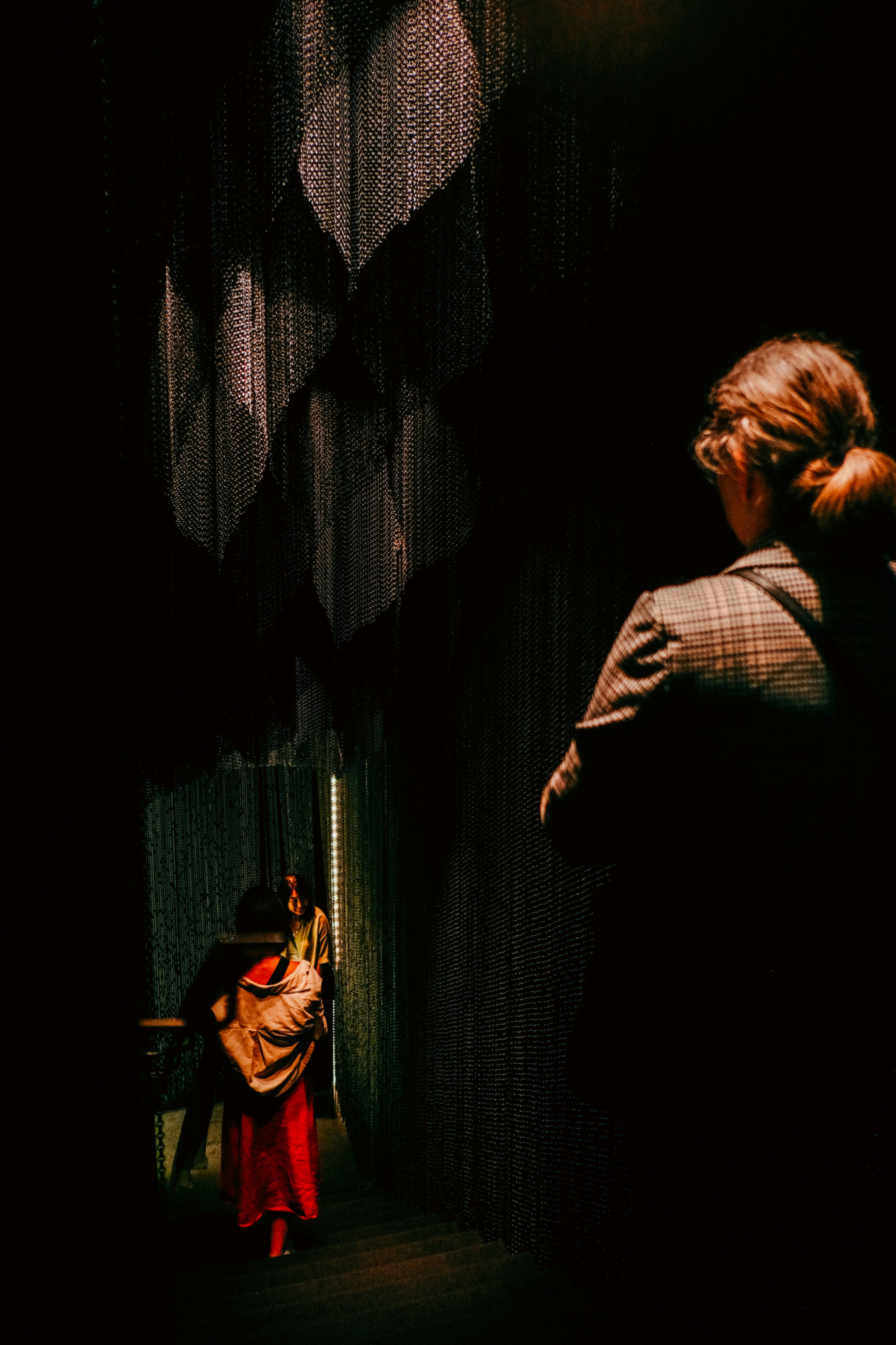 Red Dress in a Narrow Corridor of Hanging Lights