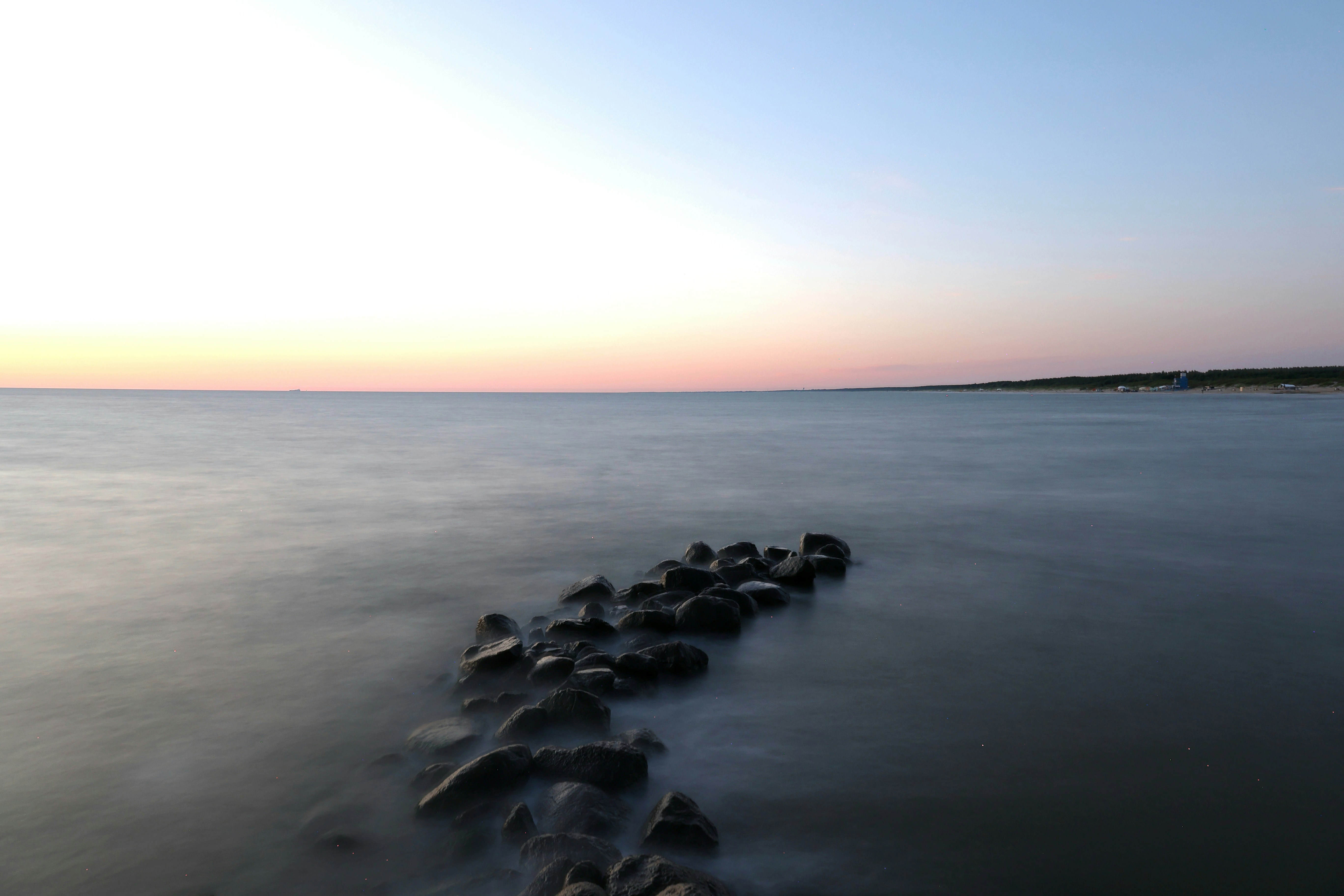 A long line of rocks sitting in the middle of a body of water