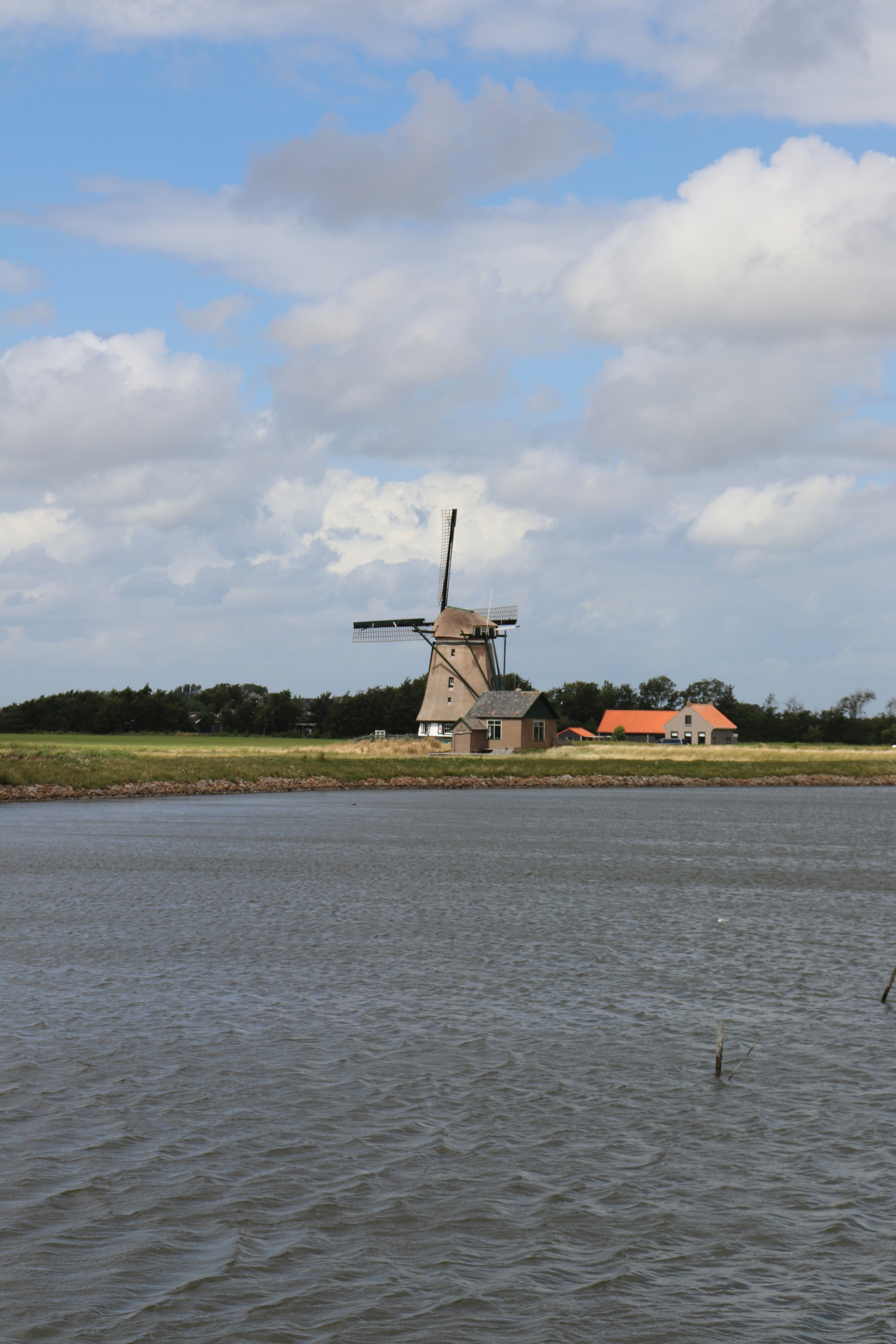 A windmill in the distance with a body of water in front of it