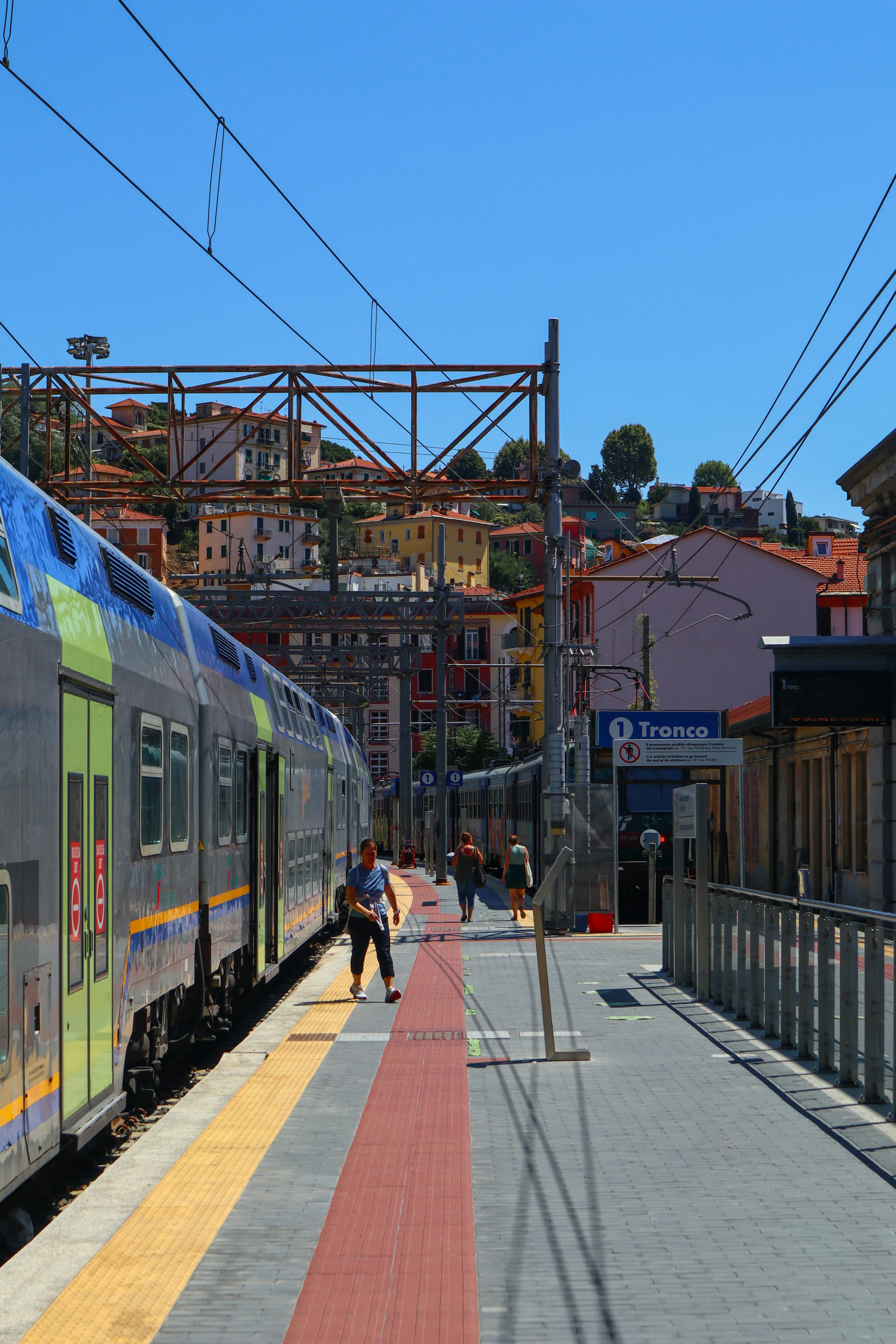 Platform Pulse: Commuters and Train in a Sunlit Italian Station