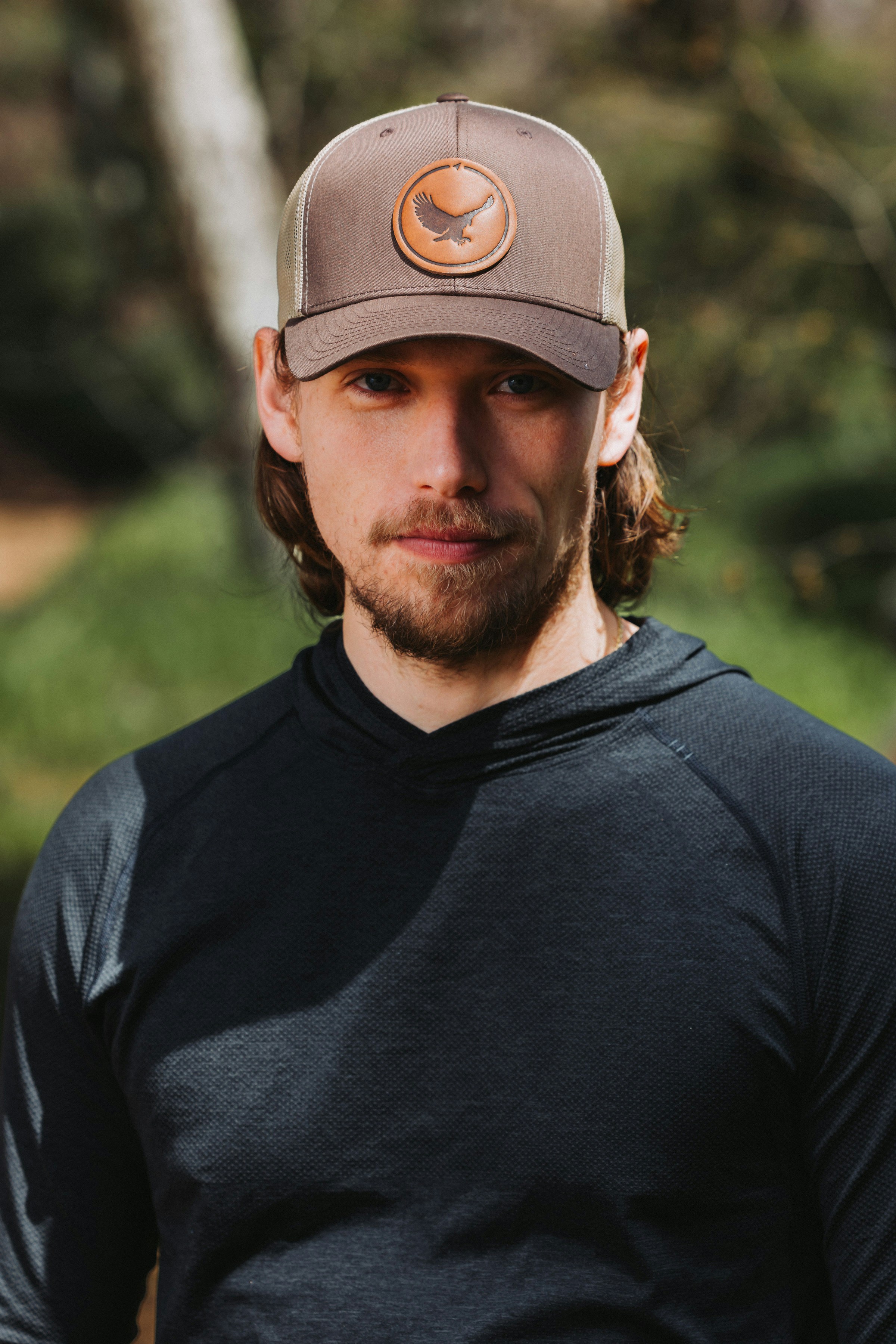 Photography by Ryan Hartford / Ecliptic Media Photography. Leather patch trucker hat being worn during a nature hike in the forest. The leather patch features an embossed American Eagle. Leather patch hat from Byward Outfitters www.bywardoutfitters.com