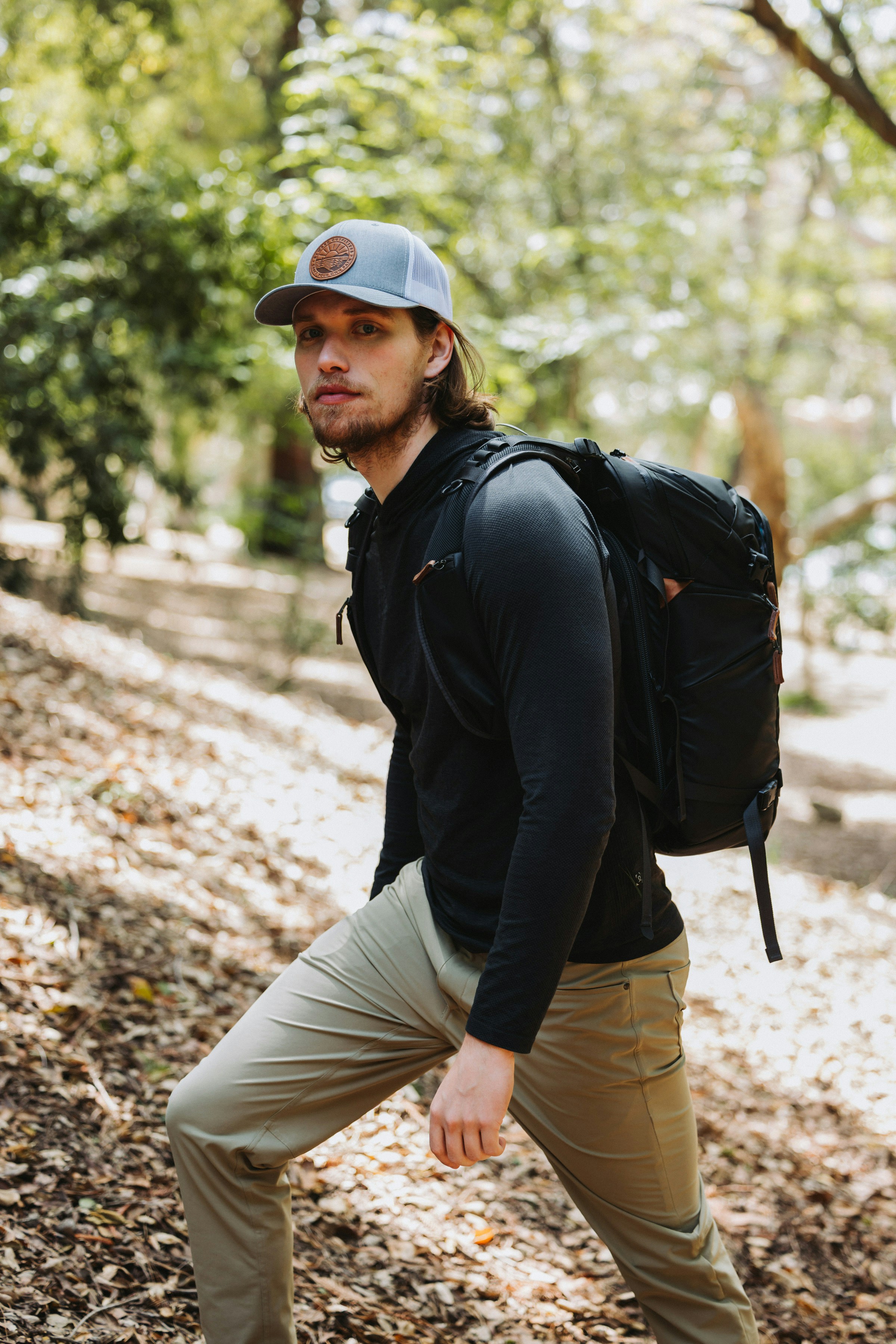 Trailbound in Sunlight: Portrait of a Hiker Navigating a Leaf-Littered Path
