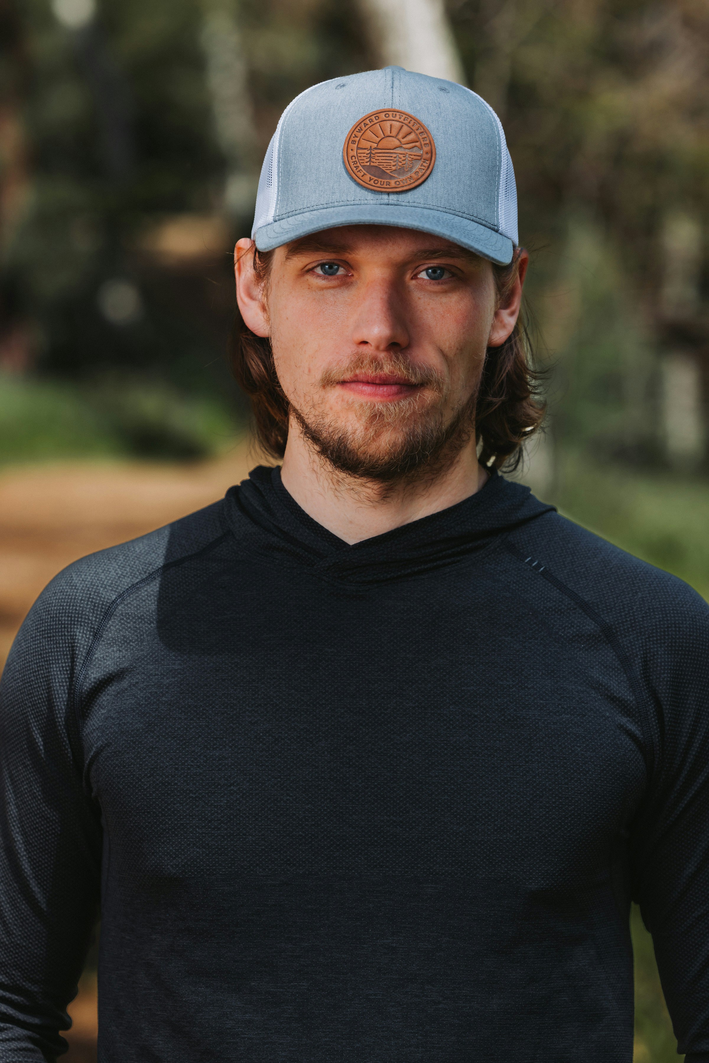 Photography by Ryan Hartford / Ecliptic Media Photography. Woman wearing our heat-pressed leather patch trucker hat in the forest during a nature hike. Leather patch hat from Byward Outfitters www.bywardoutfitters.com