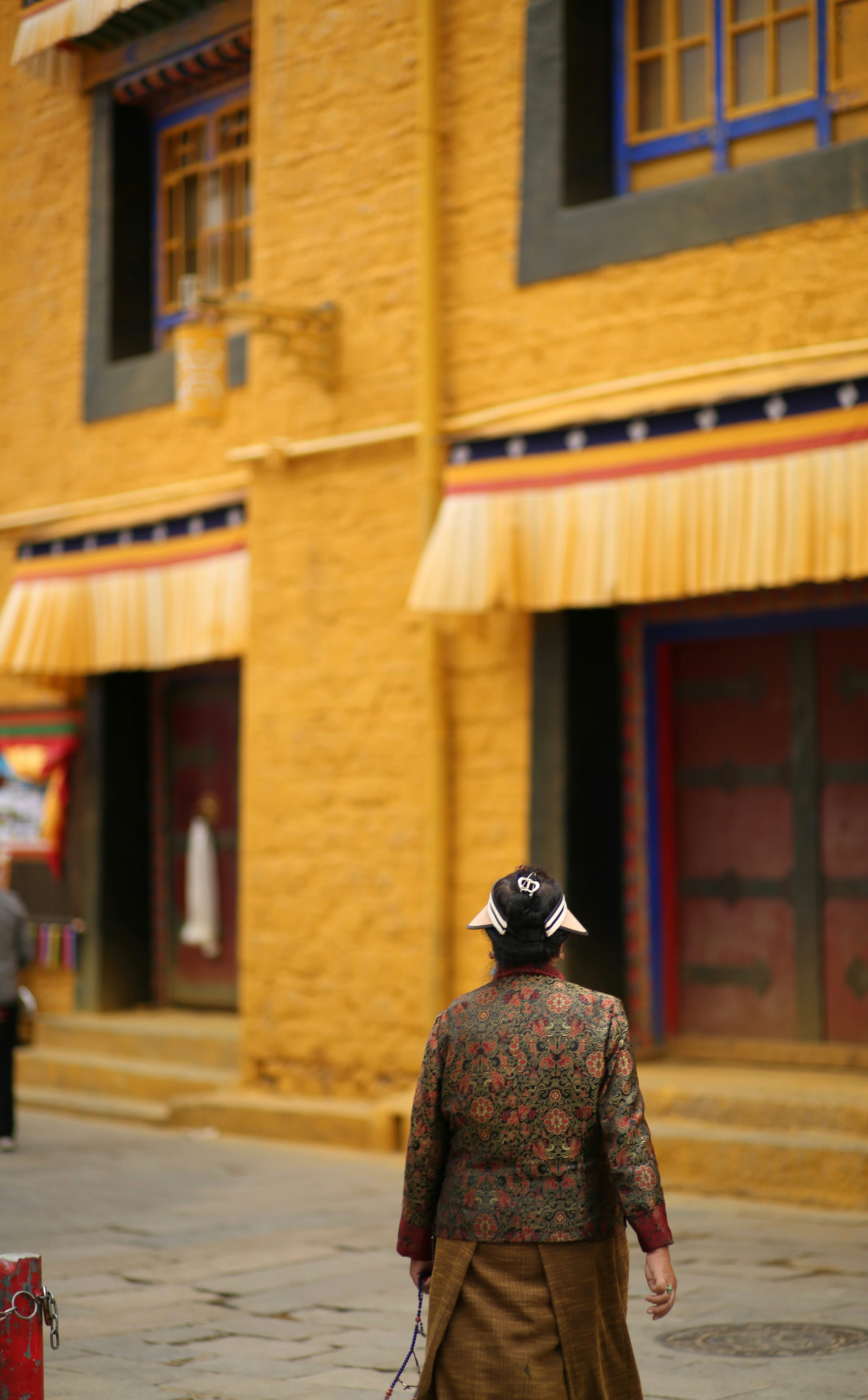 Silk and Sunlight: A Woman in Traditional Dress Walks Past Golden Facades