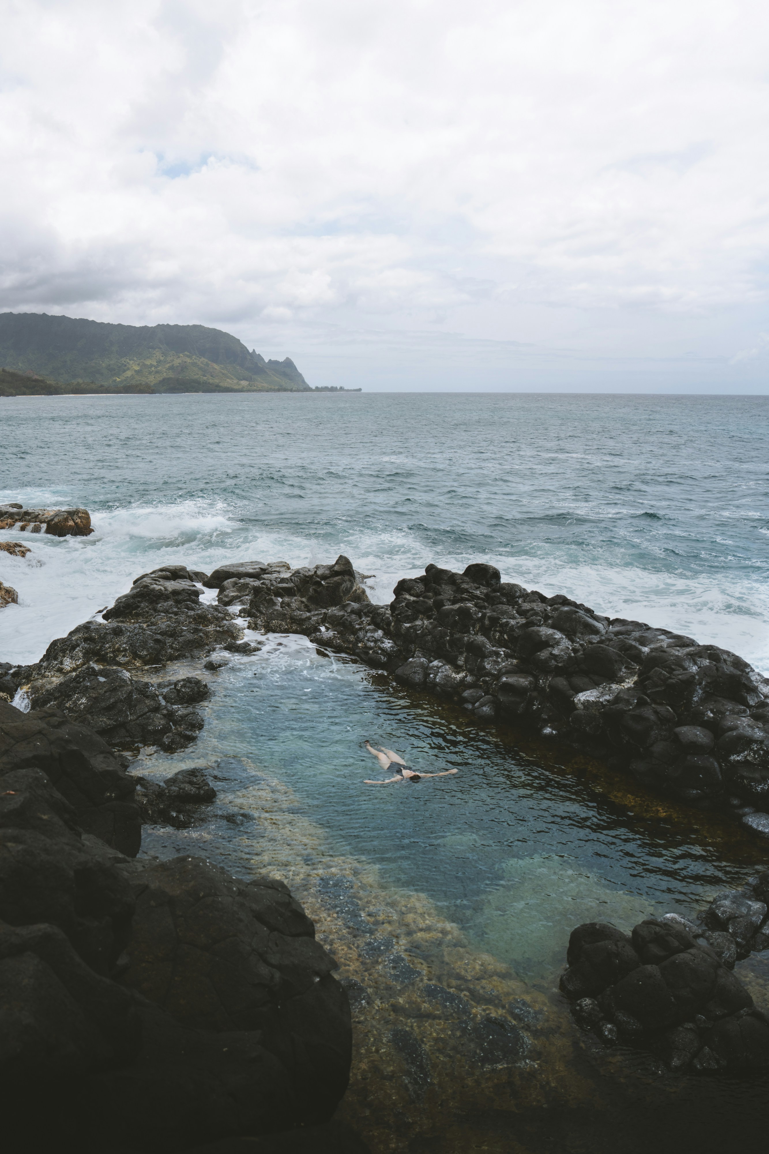 A body of water surrounded by rocks on a cloudy day photo – Free Kauai ...