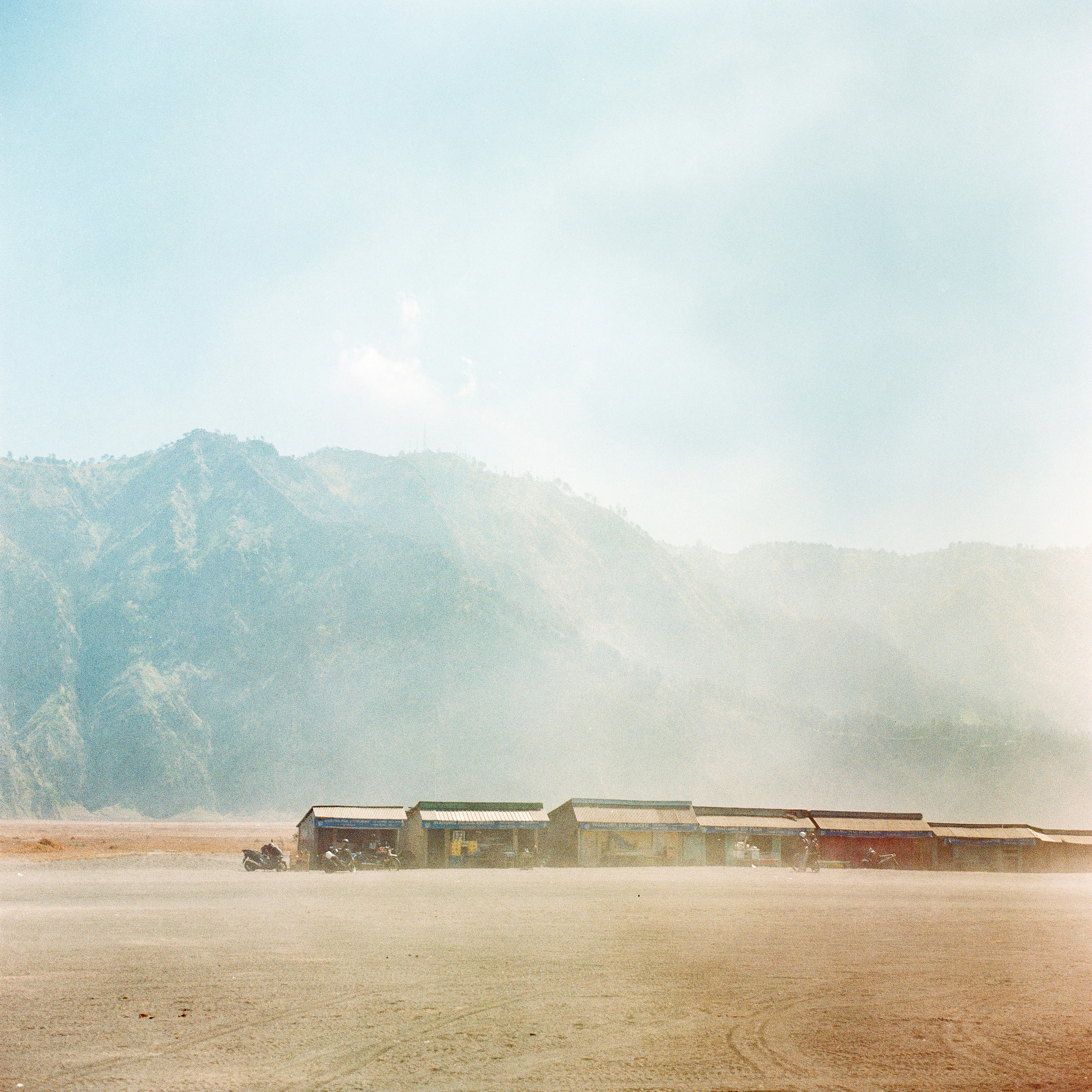 Hut Row on a Dusty Plain Beneath Misty Peaks