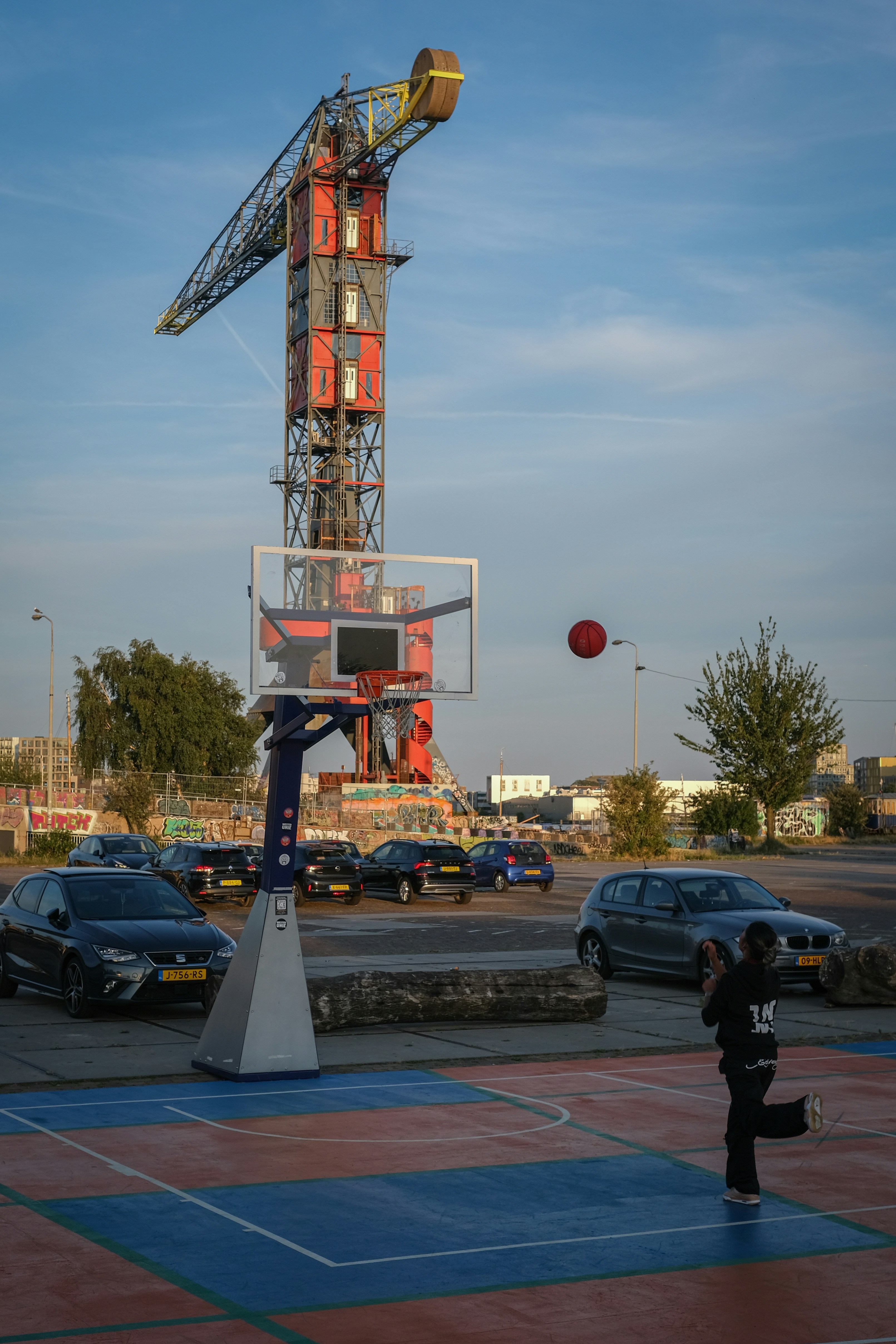 Basketball Arc Under a Towering Urban Crane