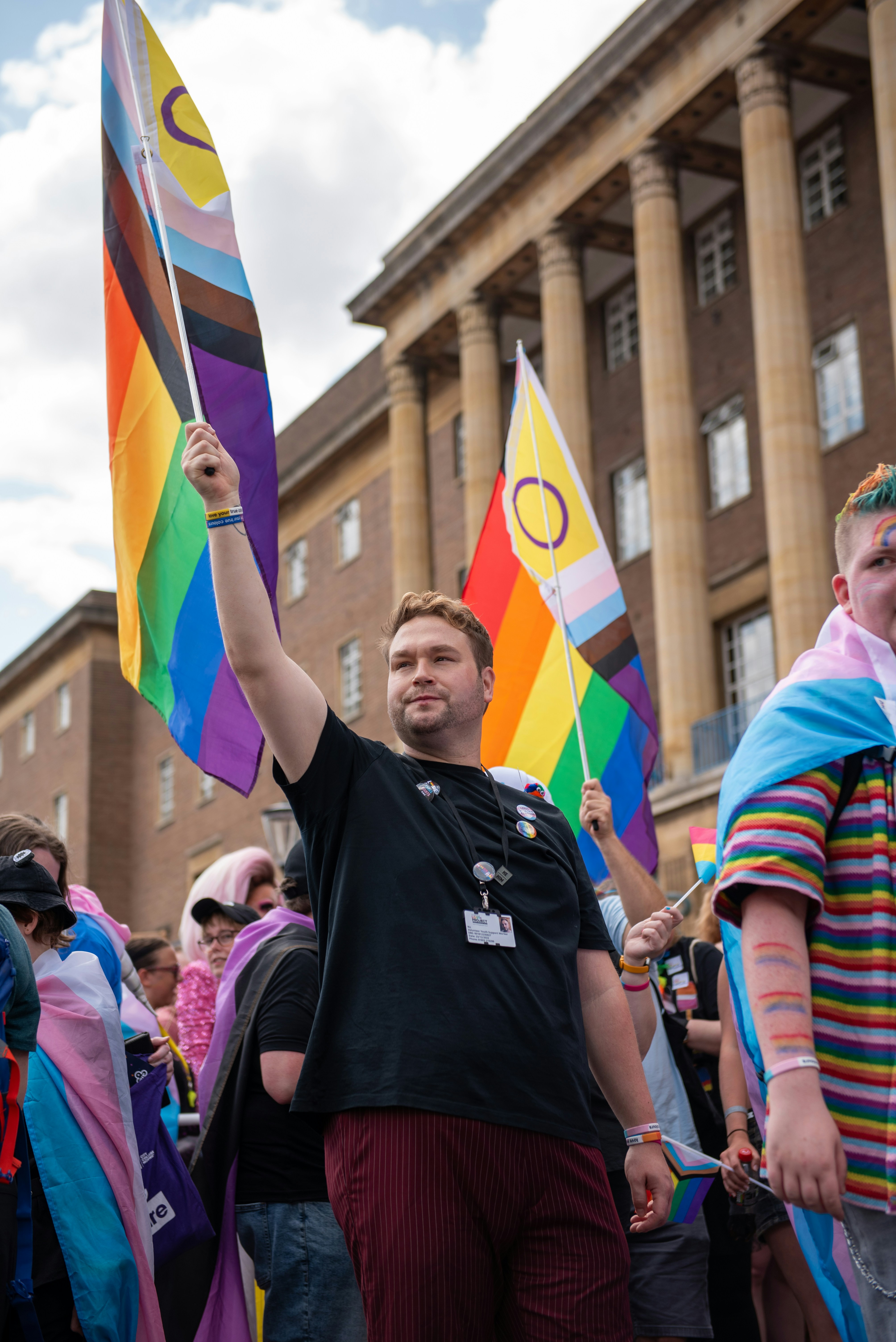 Flagbearer Among Pride Flags at a Historic Colonnade
