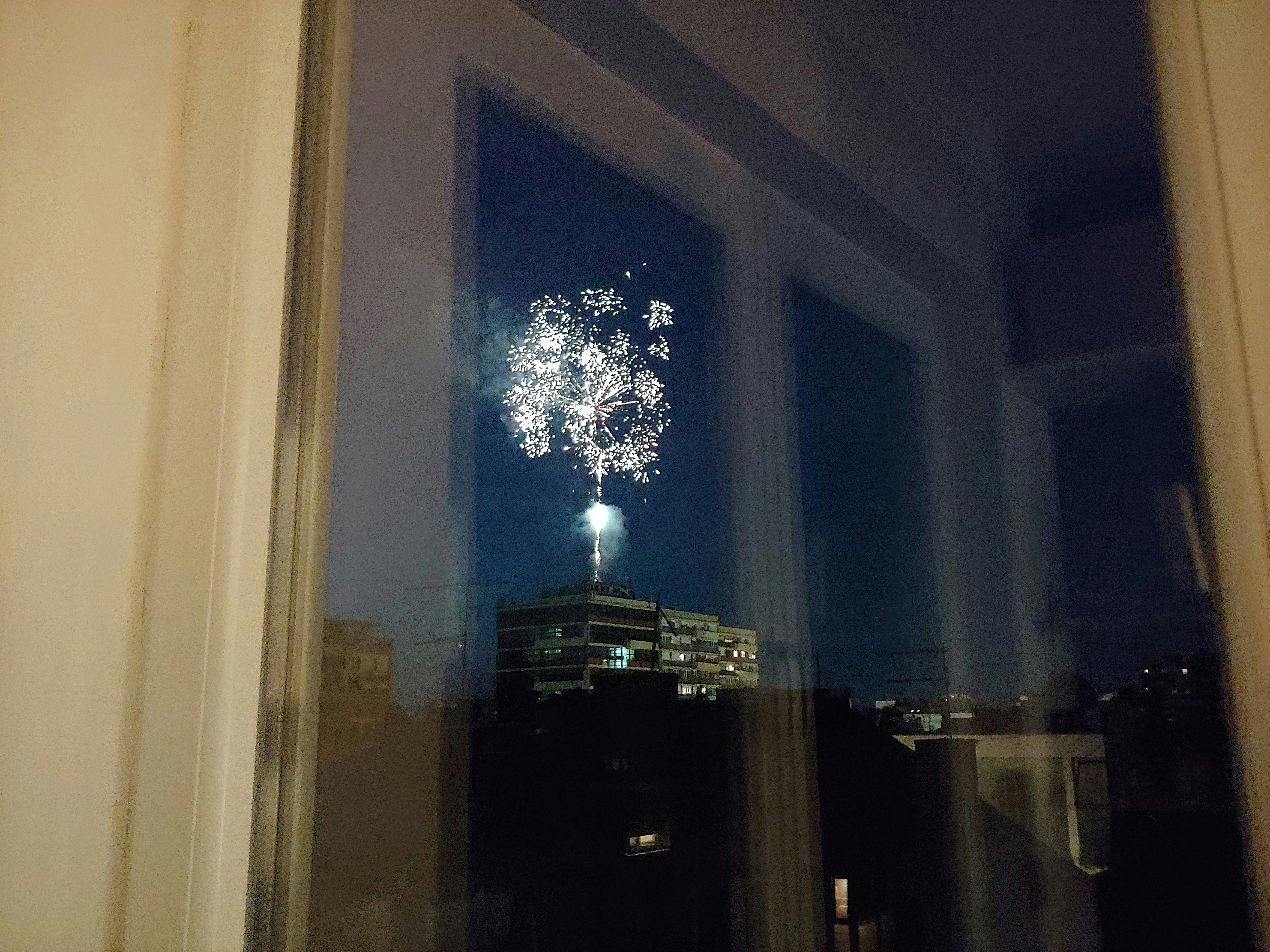 A fireworks display is seen through a window photo – Free Nature Image ...