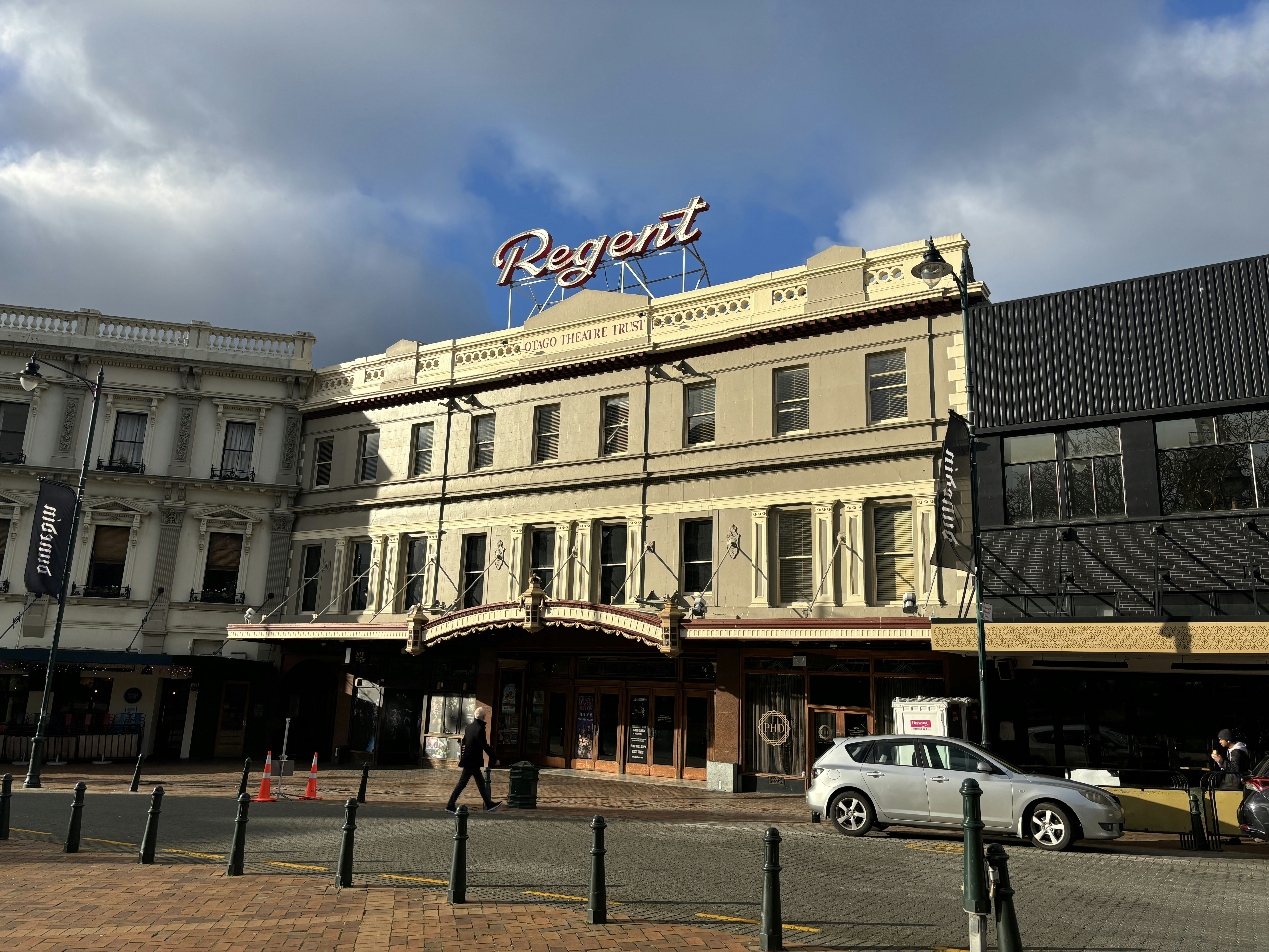 Historic building with 'Regent' sign against a backdrop of dramatic clouds and blue sky.