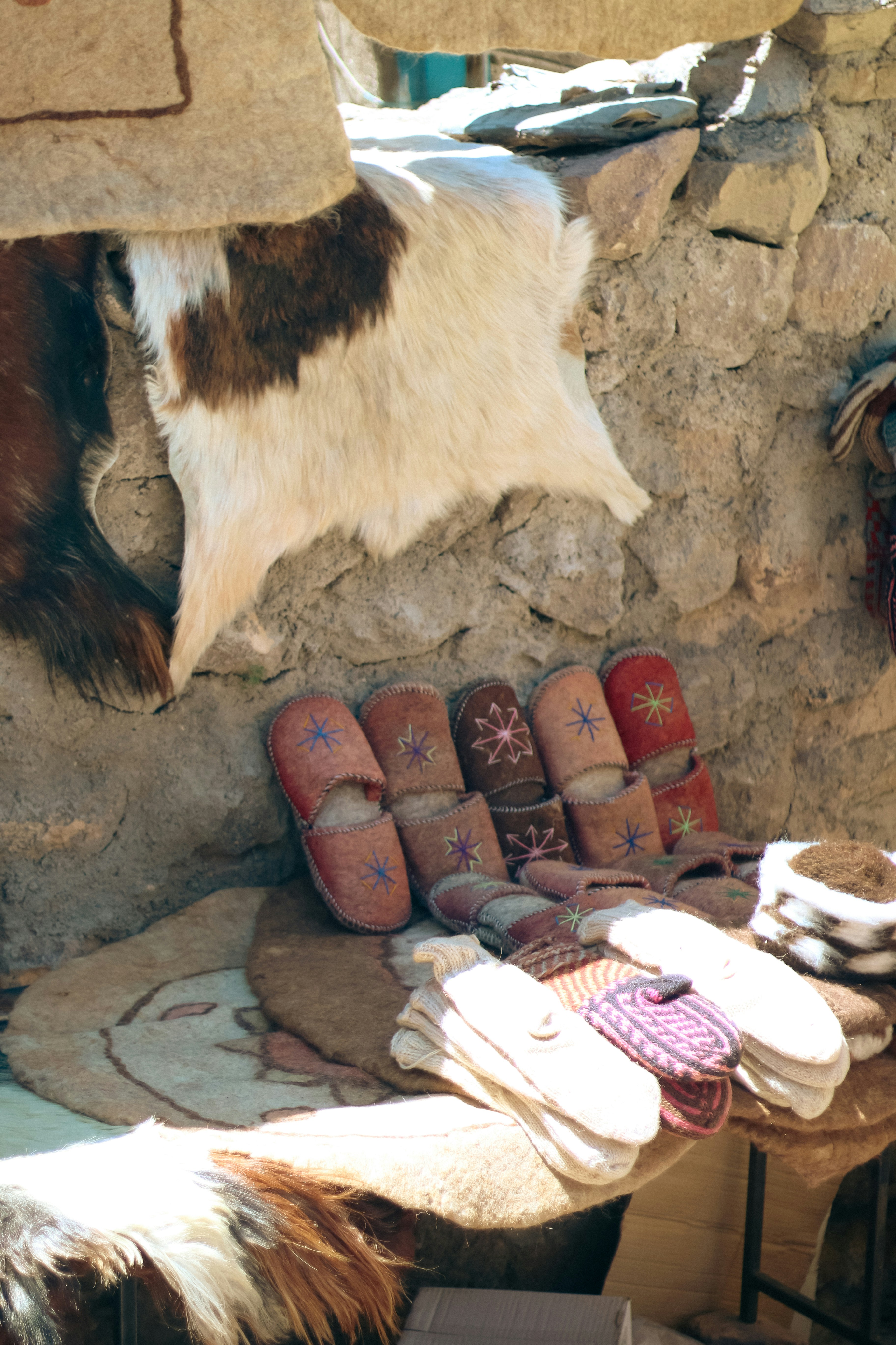 Star-stitched Slippers Framed by Fur on a Weathered Stone Wall
