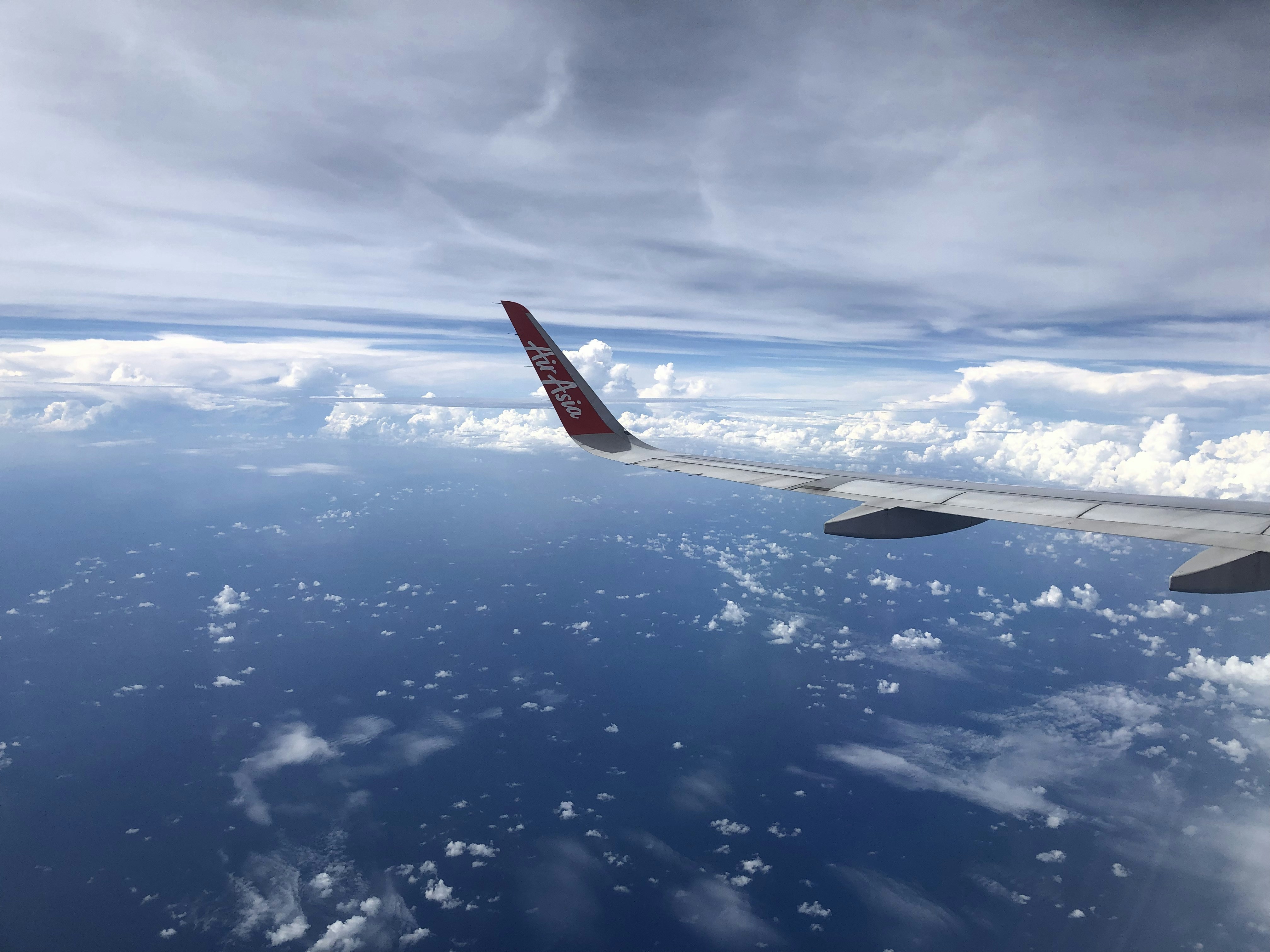 Crimson Winglet Across a Velvet Blue Sky: Cloudscape from a Window Seat