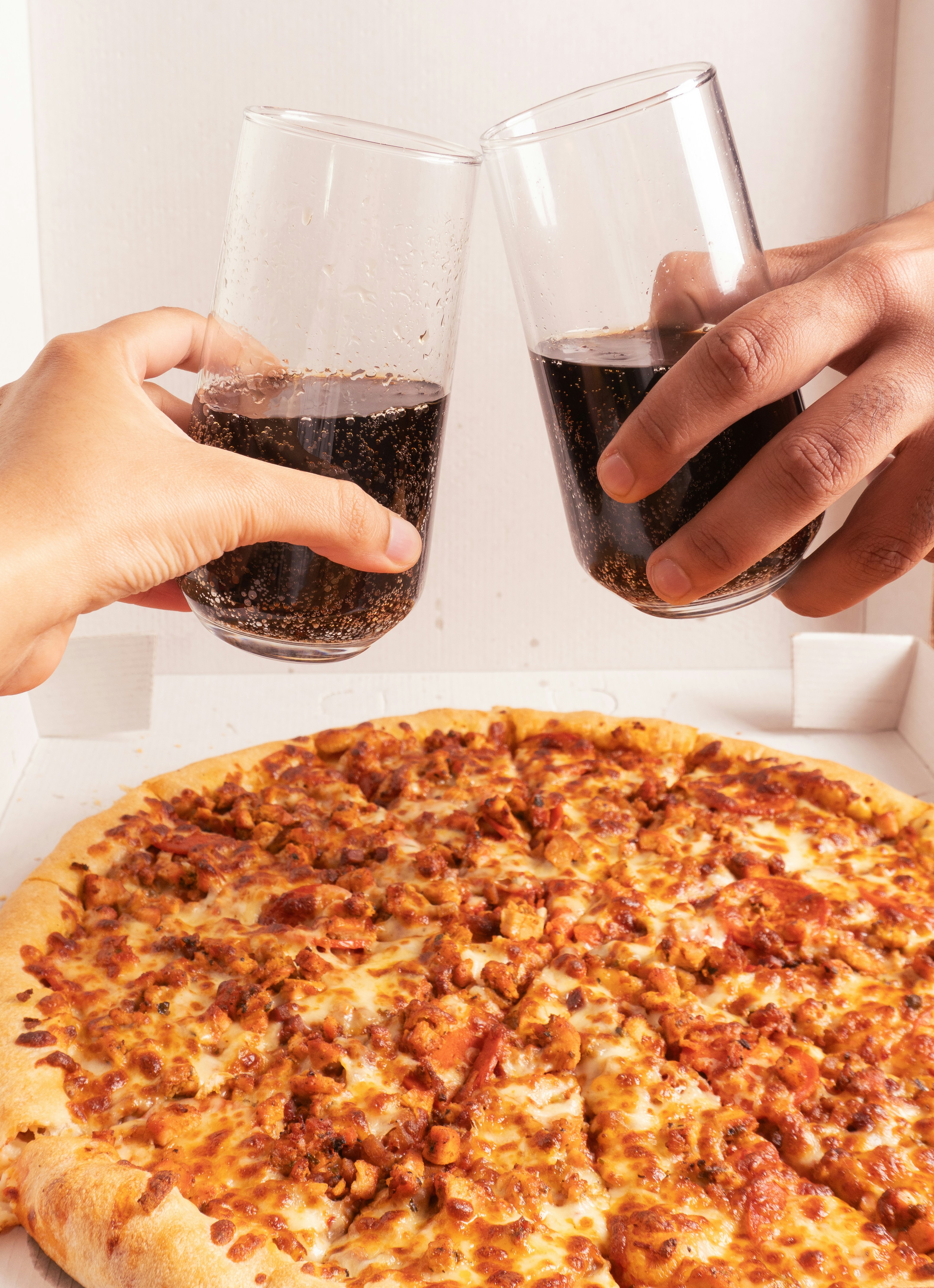 Toast Above the Crust: Two Glasses Lifted Over a Pepperoni Pizza