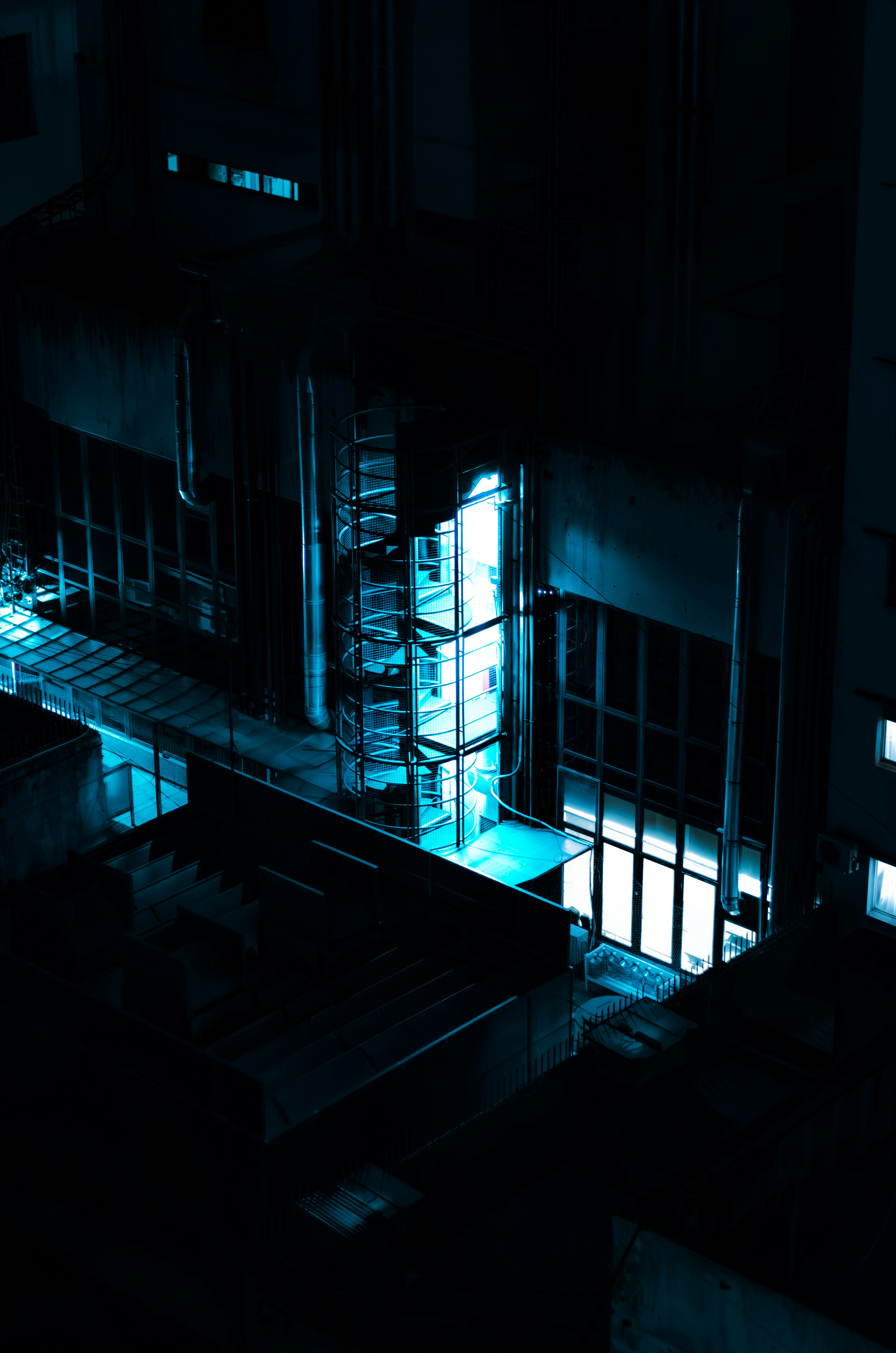 Blue Neon Staircase Illuminates a Midnight Factory Facade