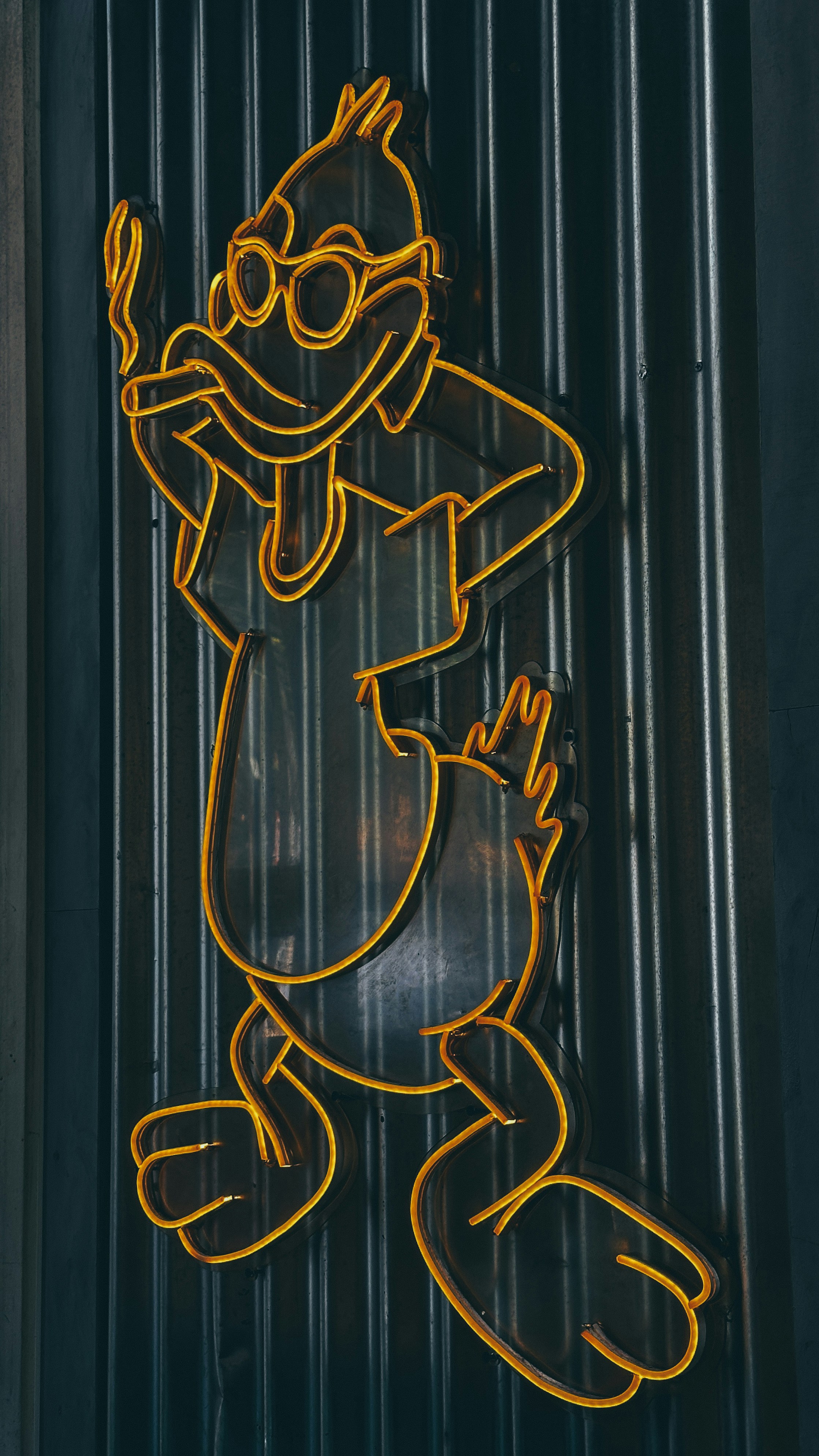 Neon Rooster Struts Across a Dark Corrugated Wall