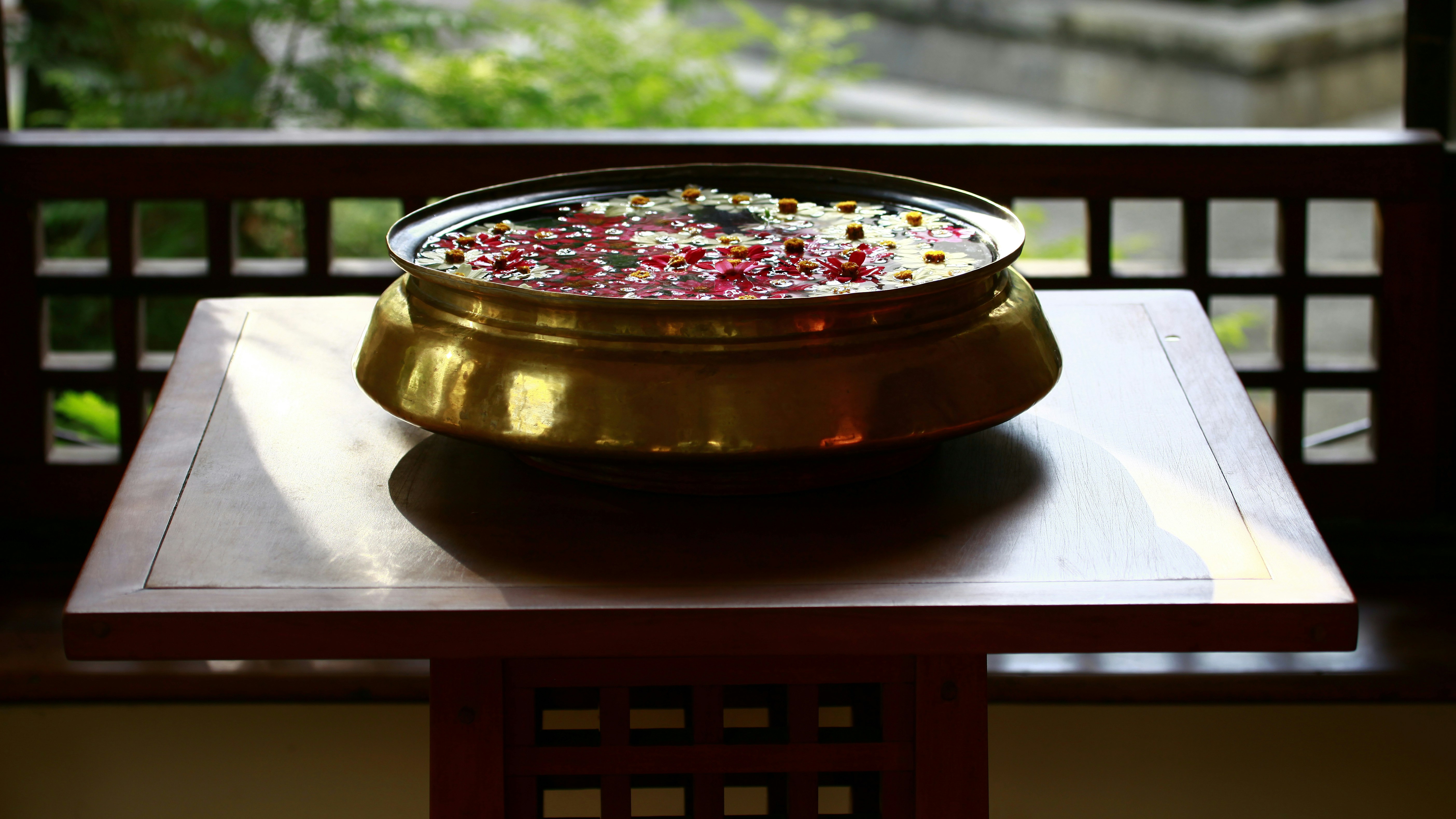 Petaled stillness: brass bowl on sunlit teak balcony