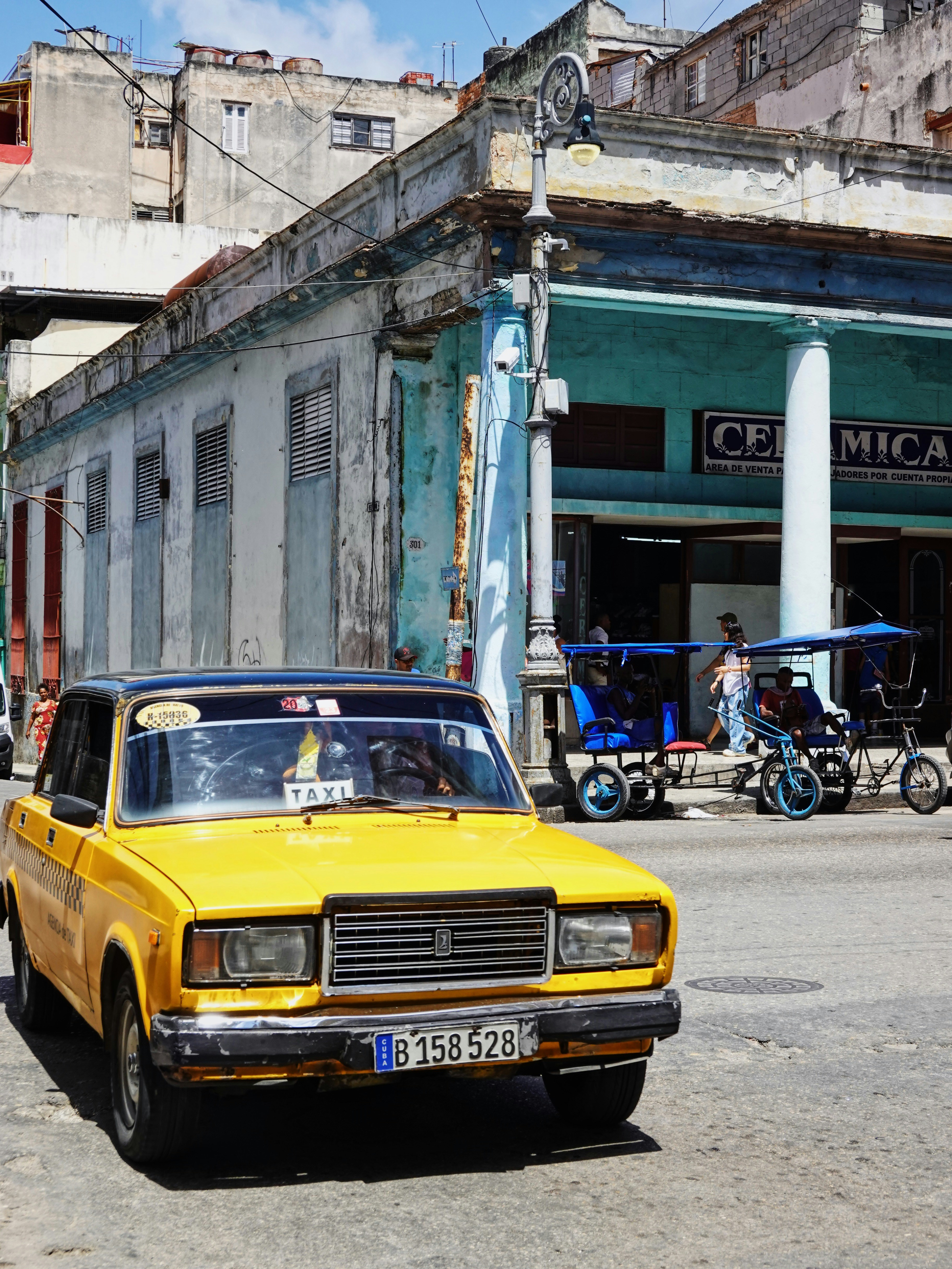 A yellow taxi cab driving down a street next to tall buildings photo ...