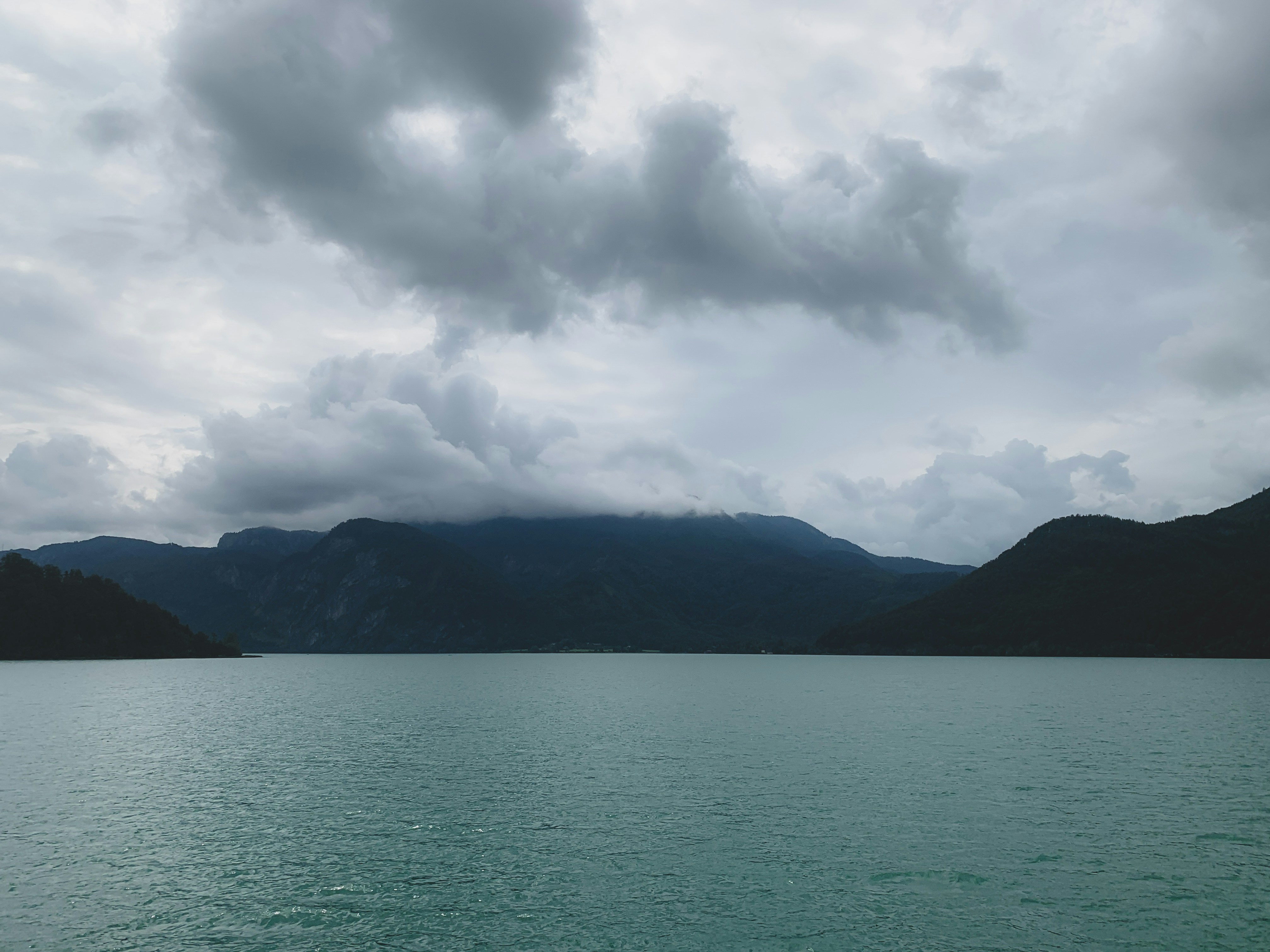 Serene lake with dark mountains under a cloudy sky.