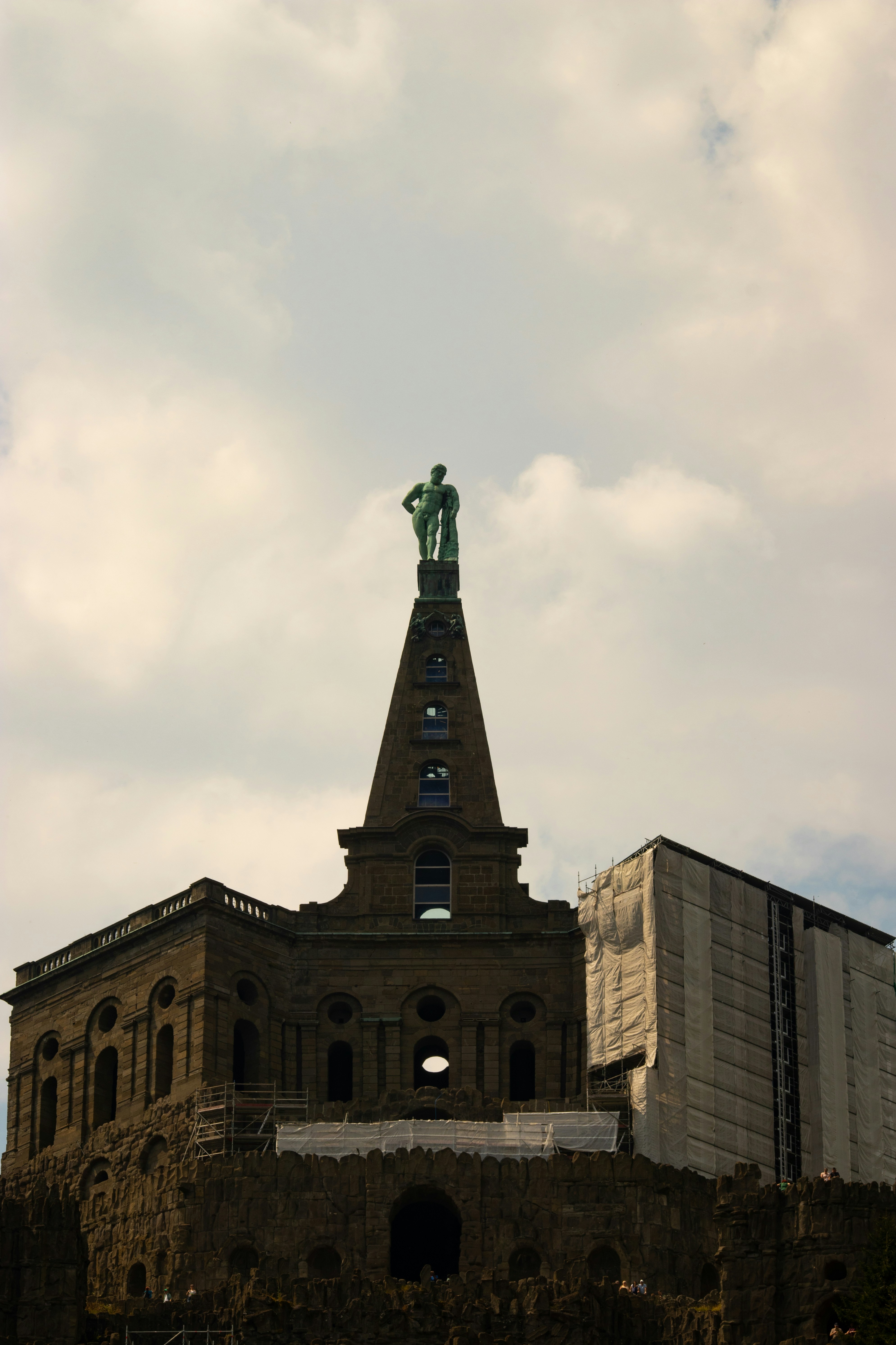 Statue atop a historic ruin under a pale sky