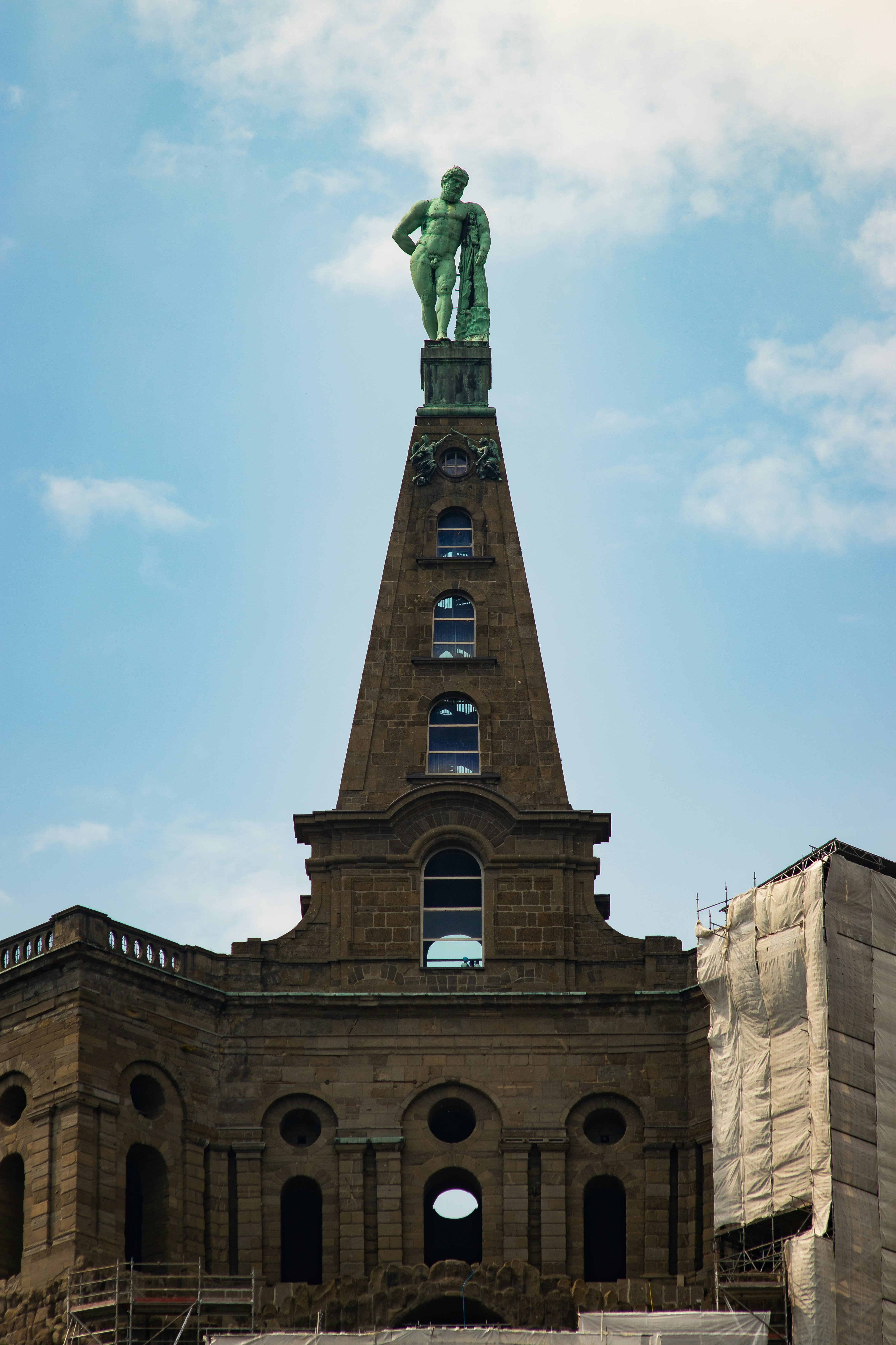 Skyward Sentinel: Bronze Figure Crowned by a Towering Brick Spire