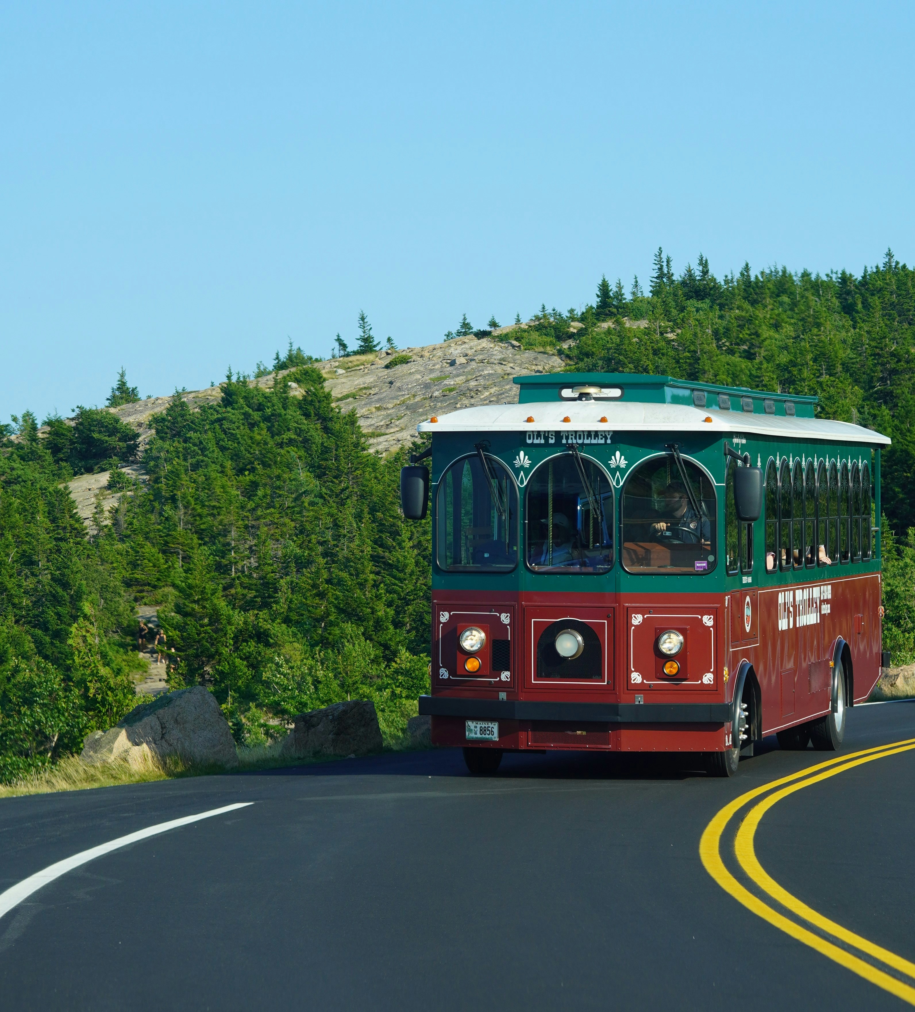 A red and green trolley driving down a curvy road photo – Free Acadia ...