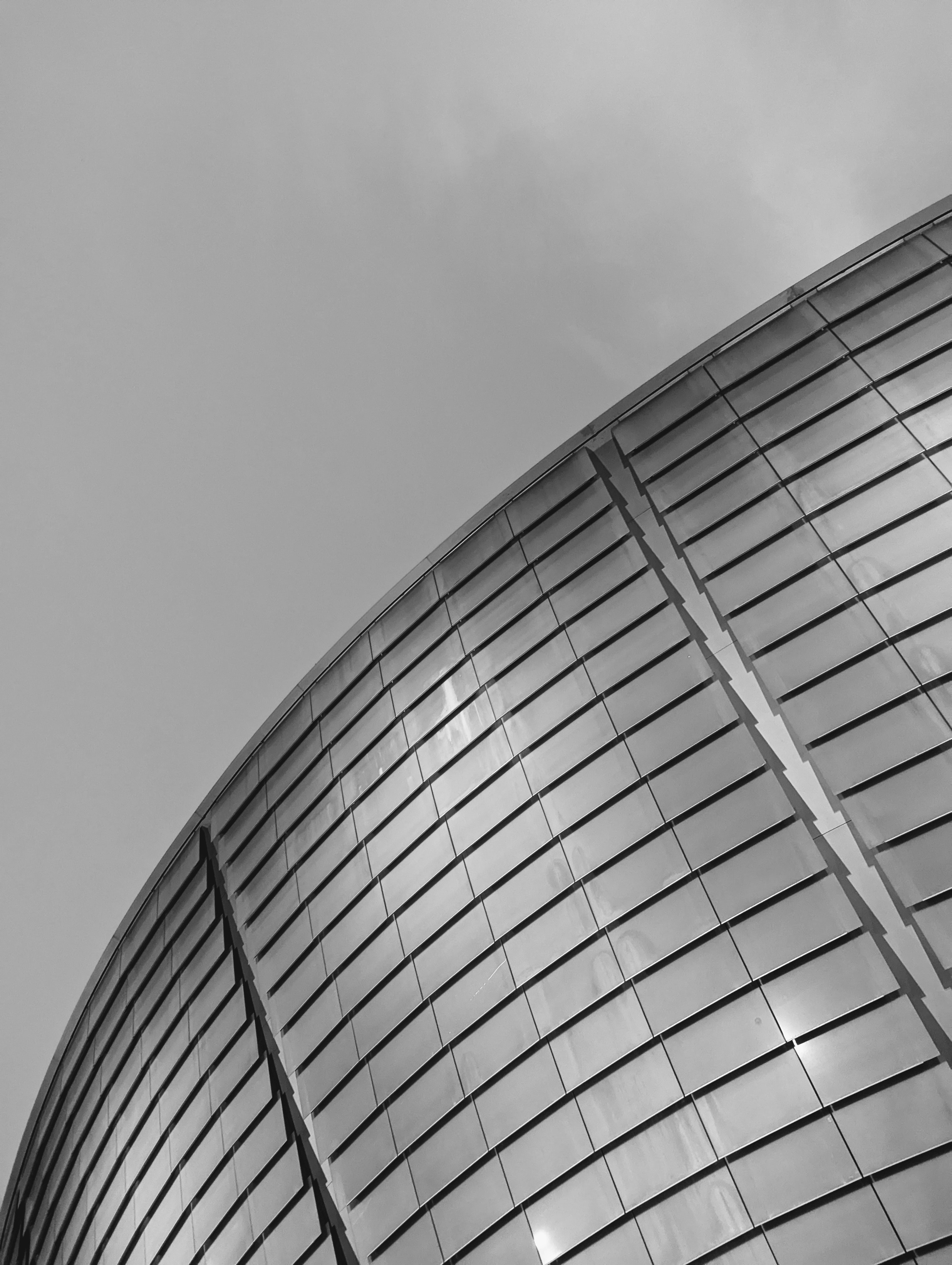 Monochrome Arch: A curved glass facade sliced by diagonal lines