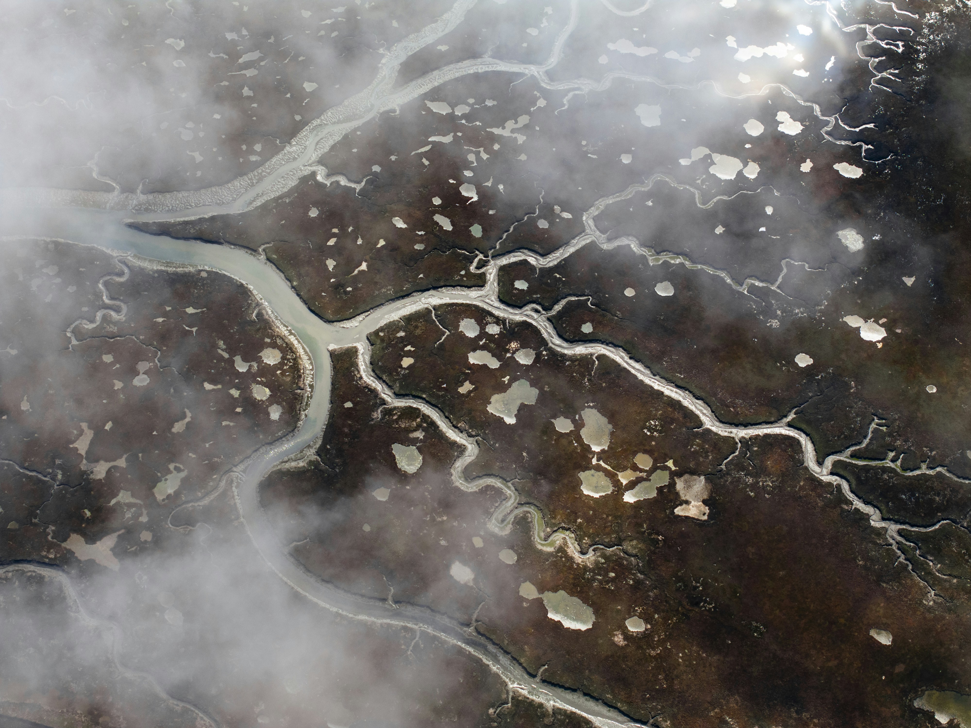 Aerial view of intricate river networks winding through a mist-covered landscape.