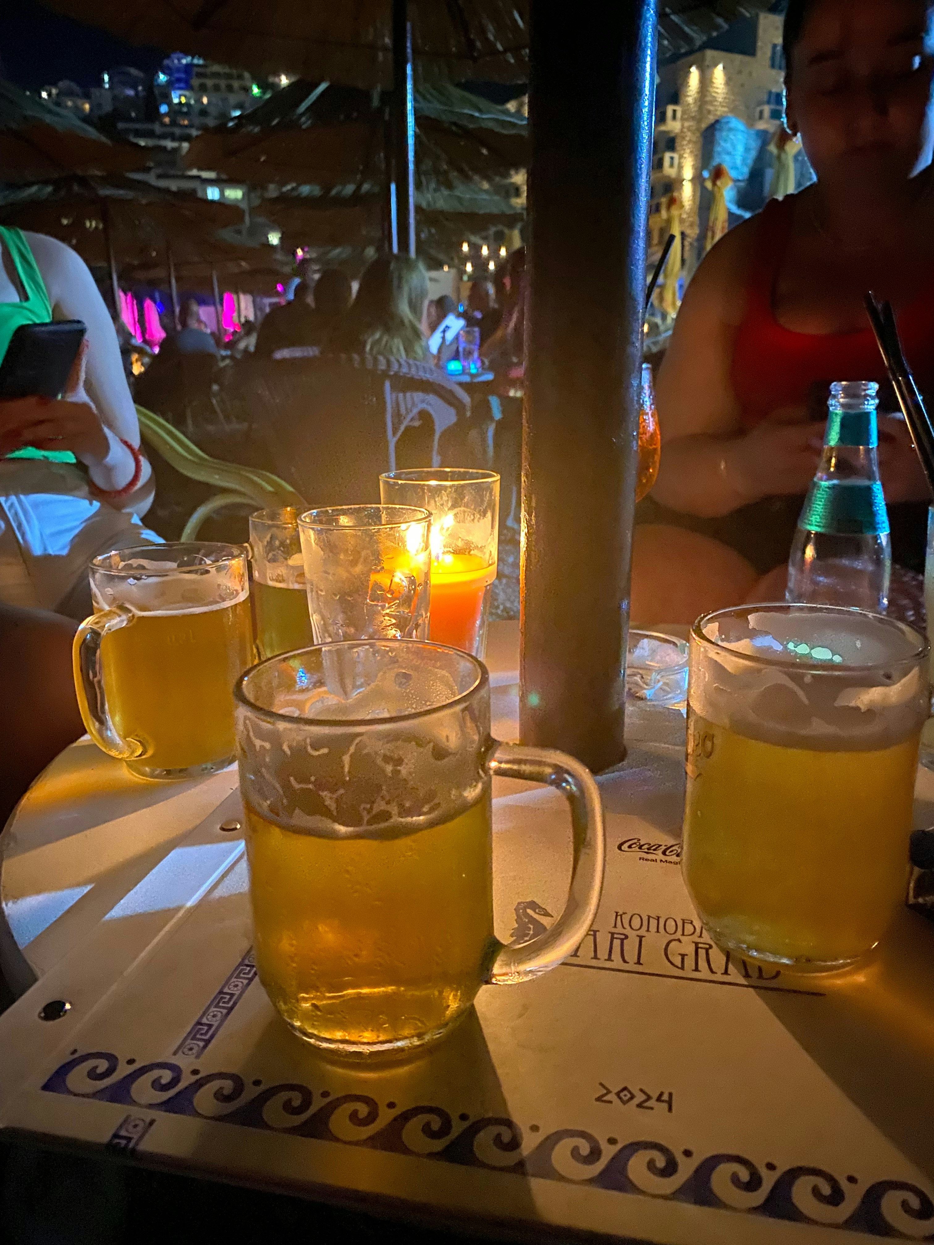 Amber Toasts Under Neon Night: Beers on a Crowded Outdoor Table