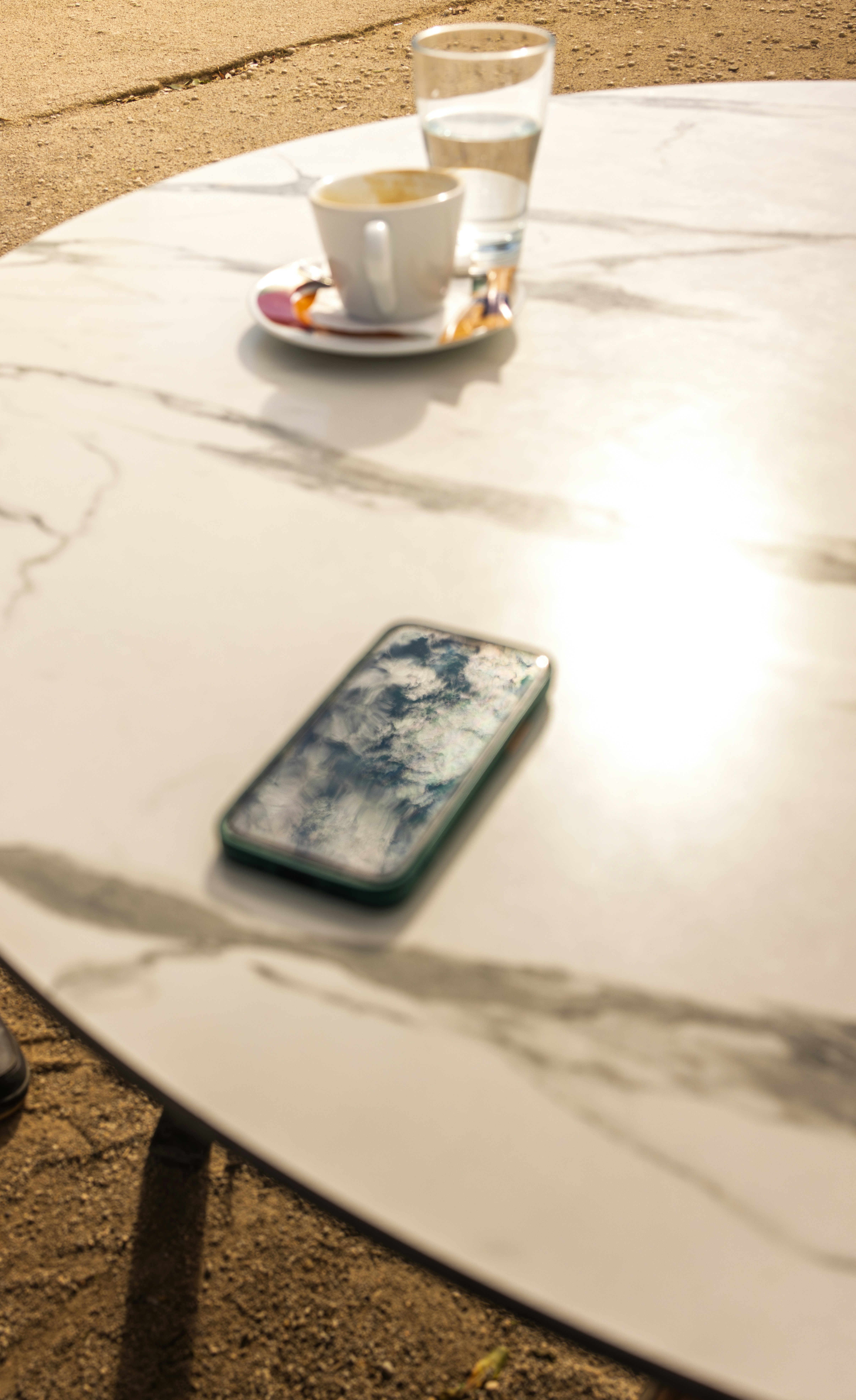 Sunlit Silence on Marble: A Phone Between Coffee and Water