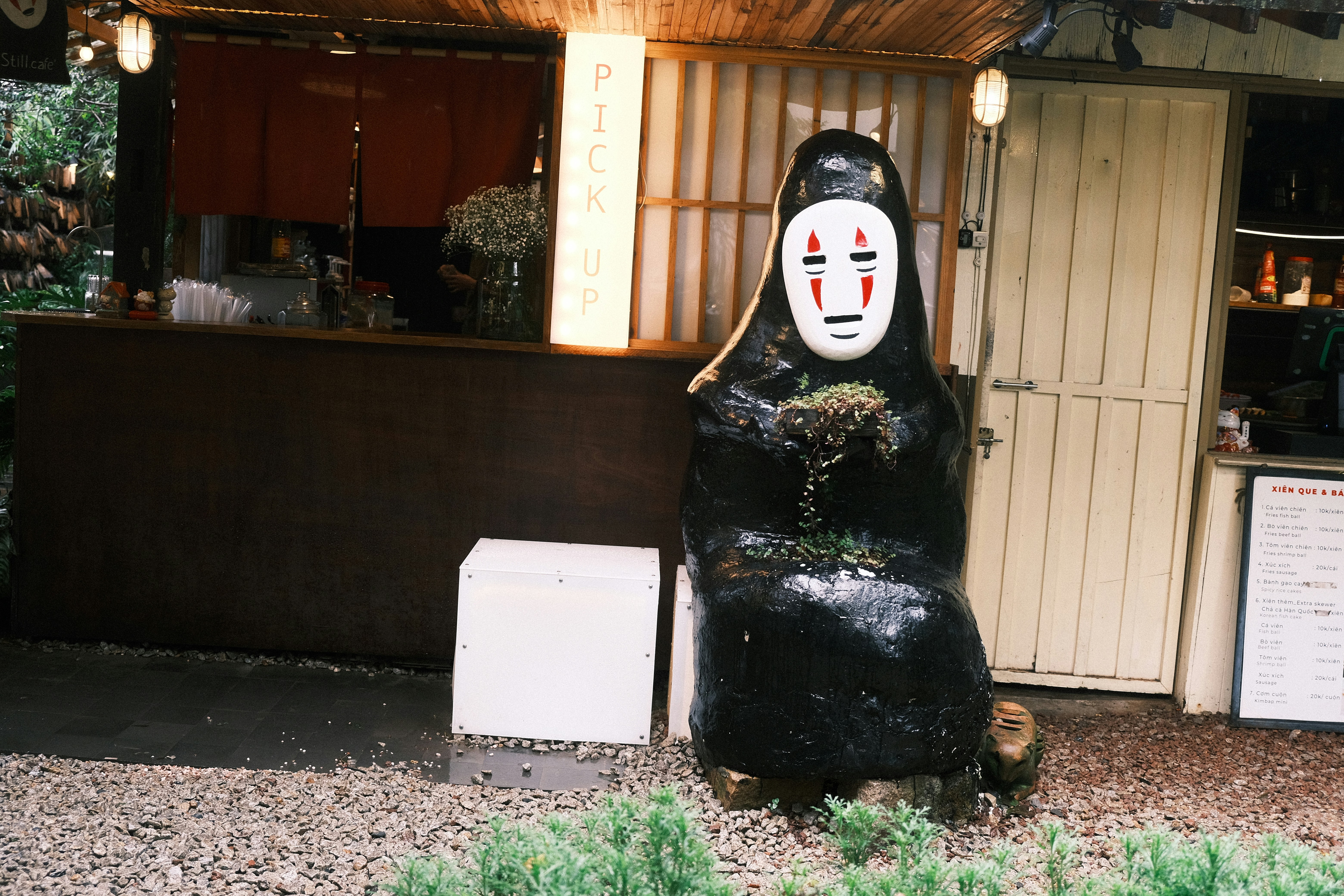 No-Face Guardian in a Sunlit Café Courtyard