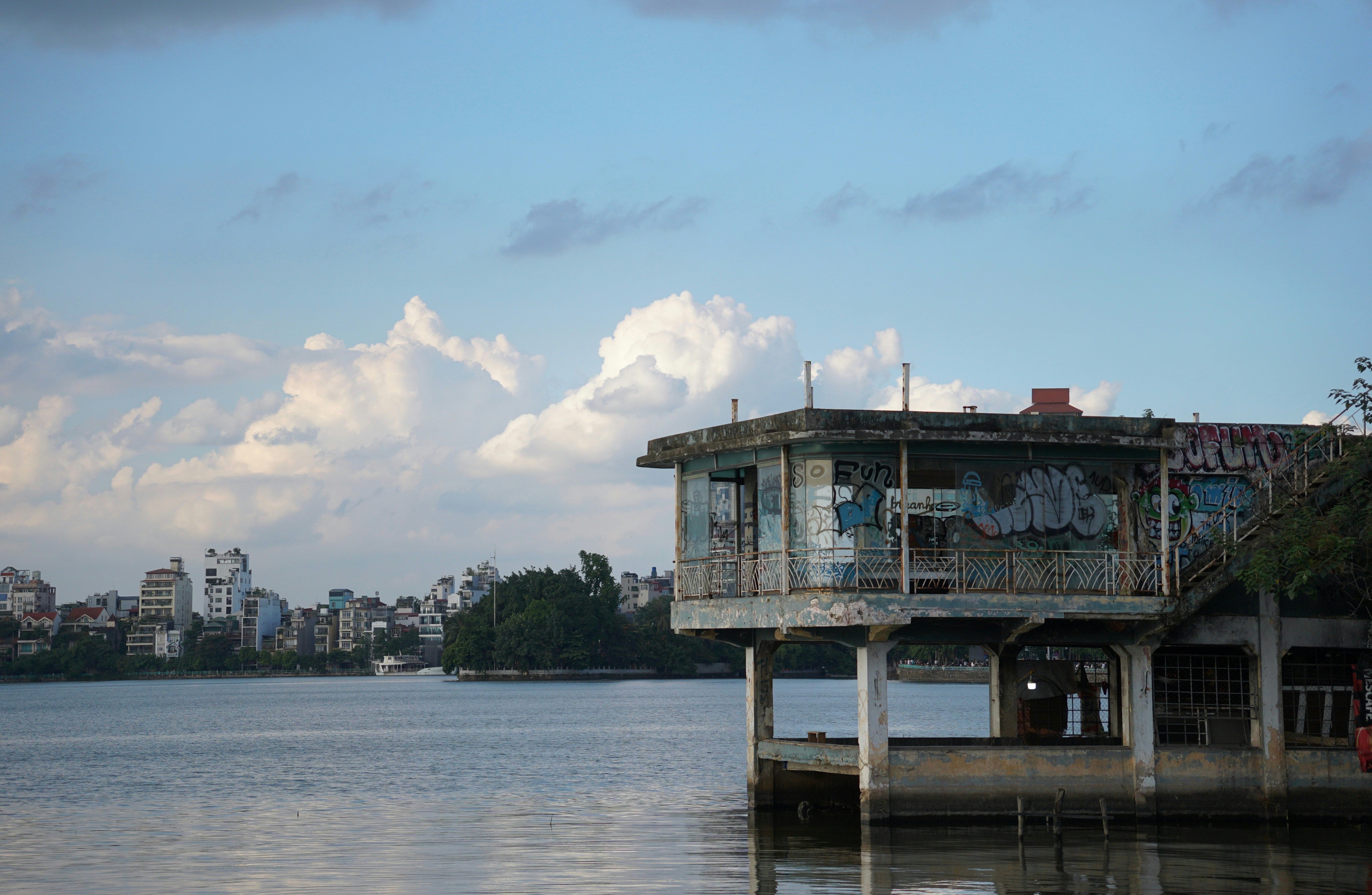 Dilapidated building extends over calm waters under a partly cloudy sky.