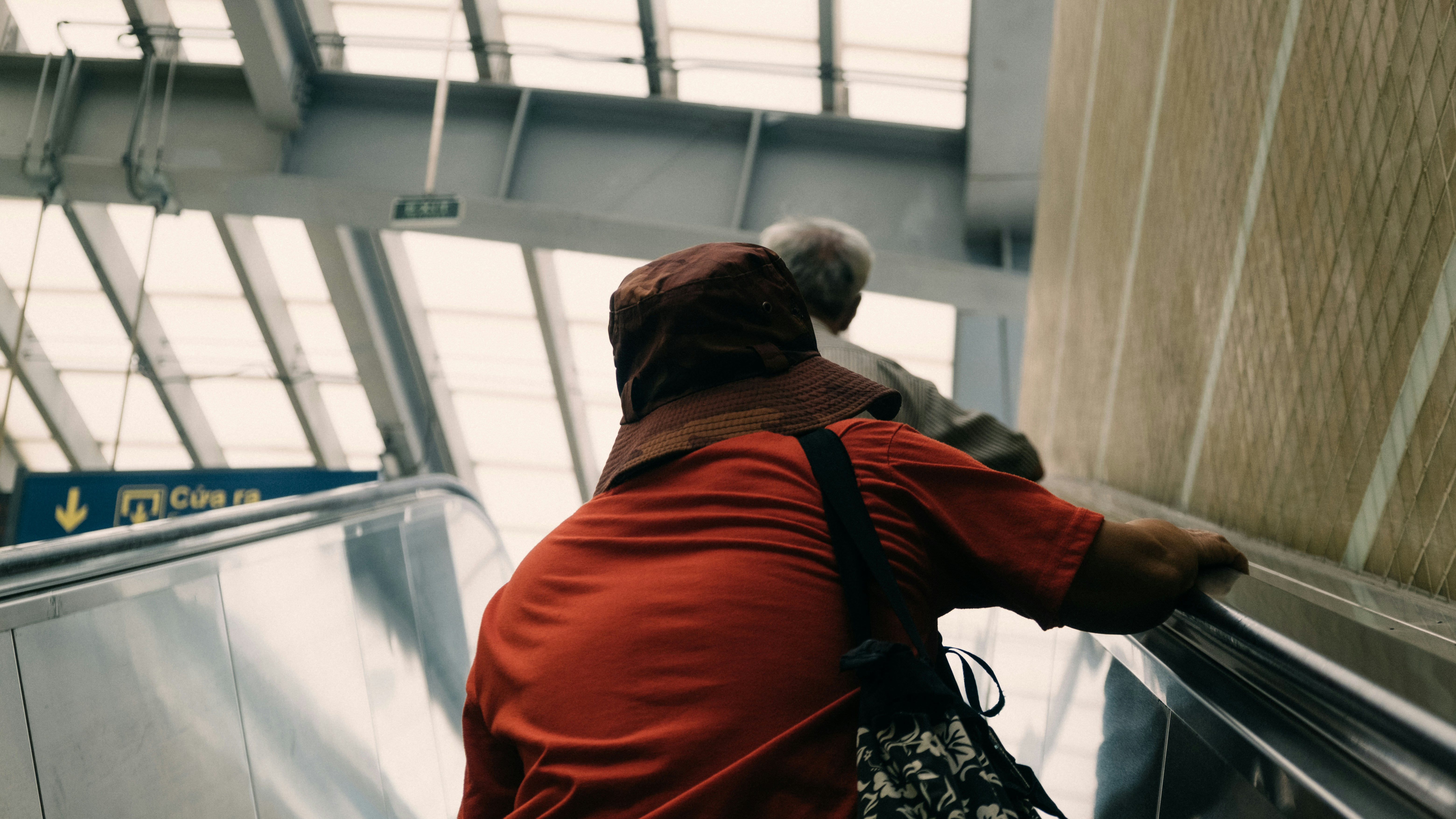 Red-Jacket Traveler Climbing the Escalator into the Light