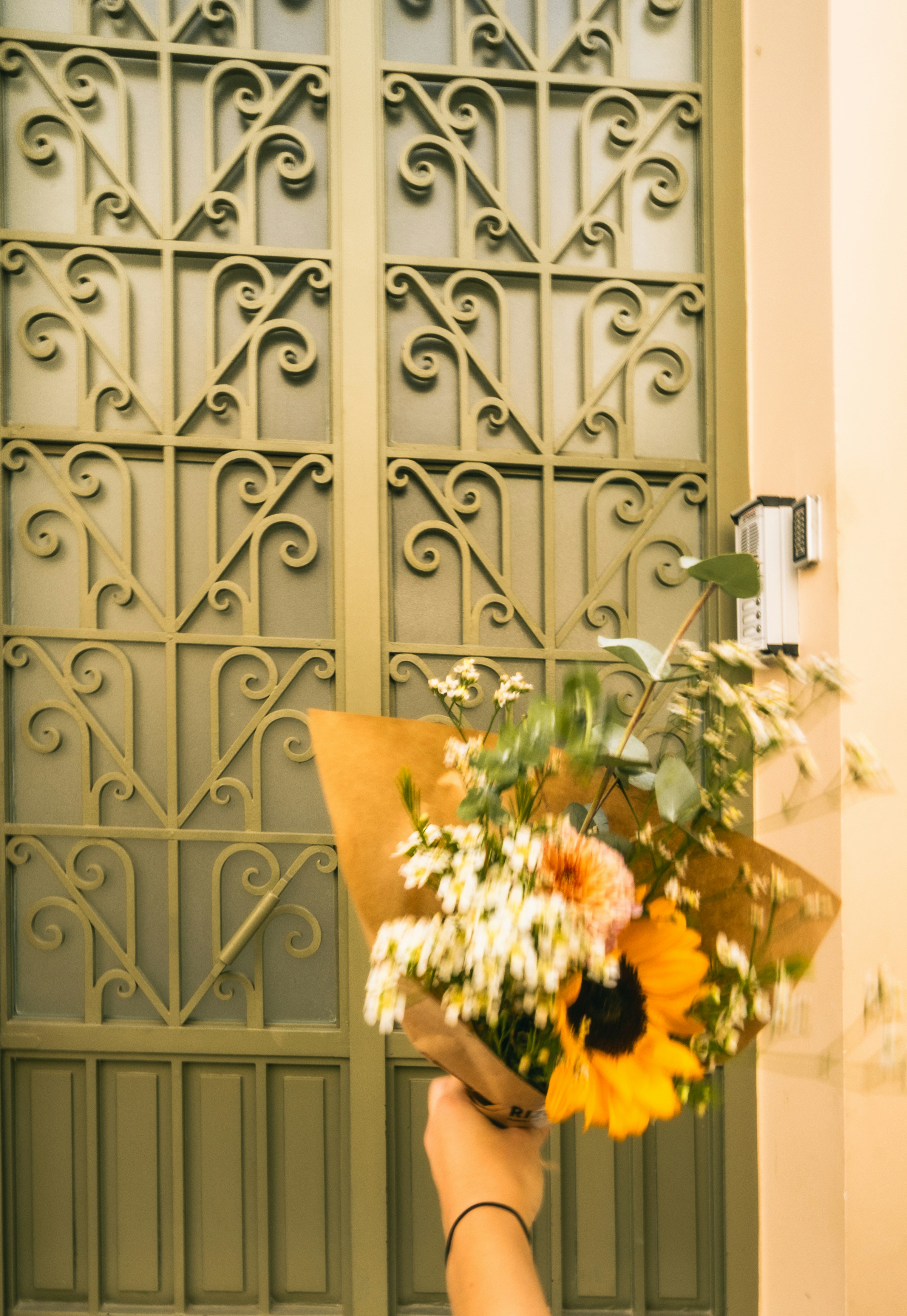 Sunflower bouquet pressed against an ornate gate at golden hour