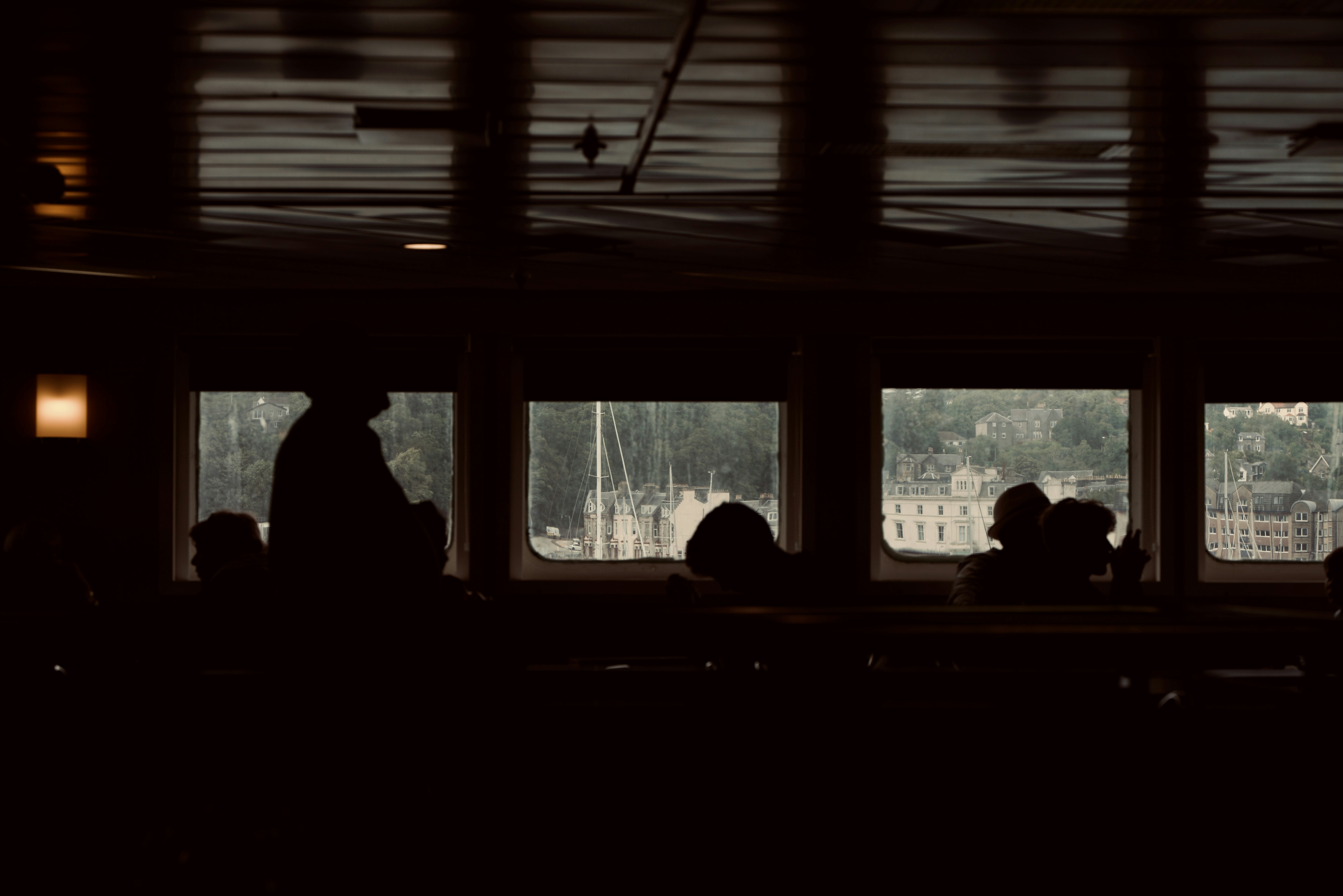 Dusk in the Windowed Cabin: Silhouettes Against a Harbor View