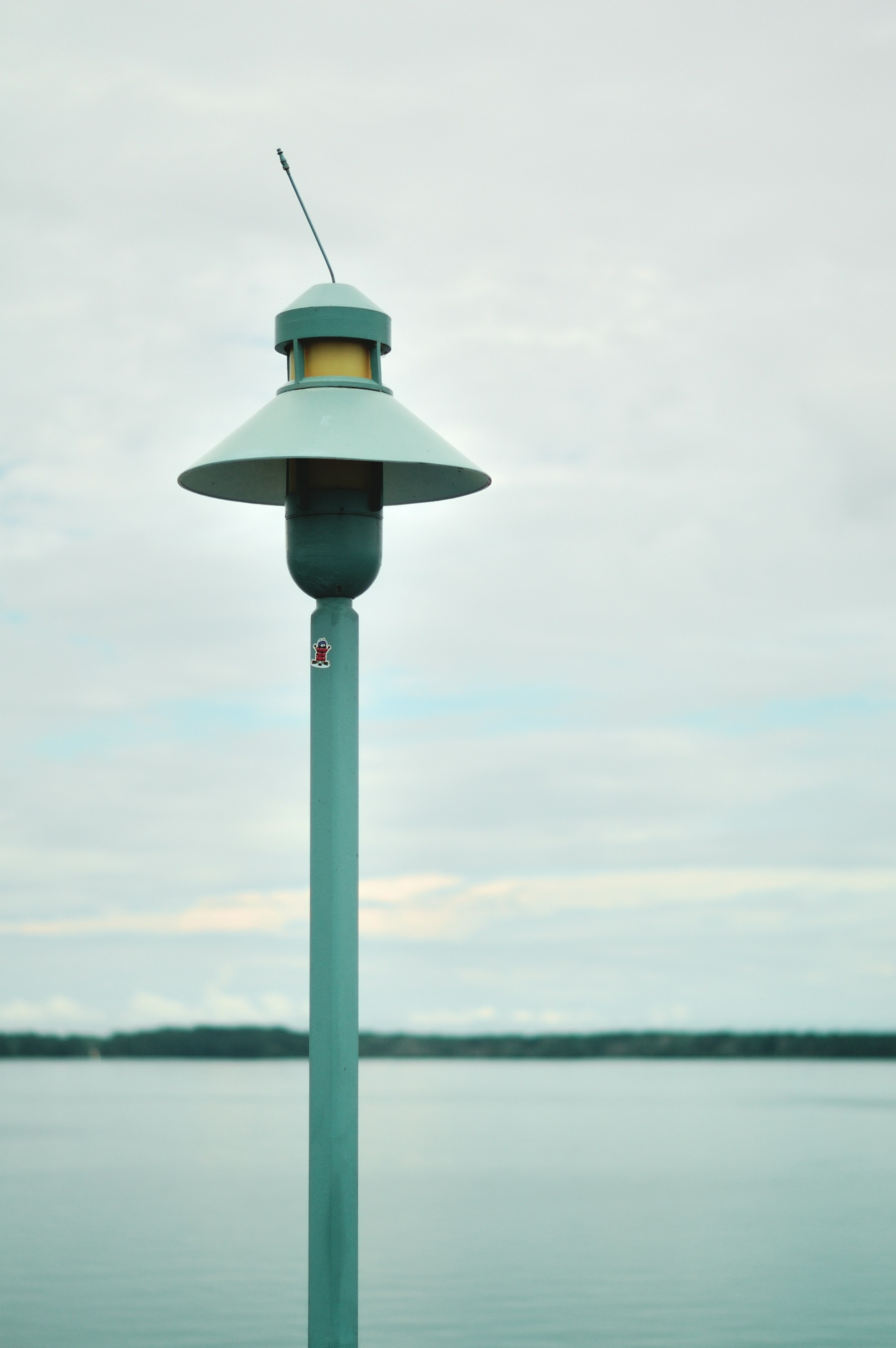 Teal Lamppost Standing Over a Quiet Lake Horizon