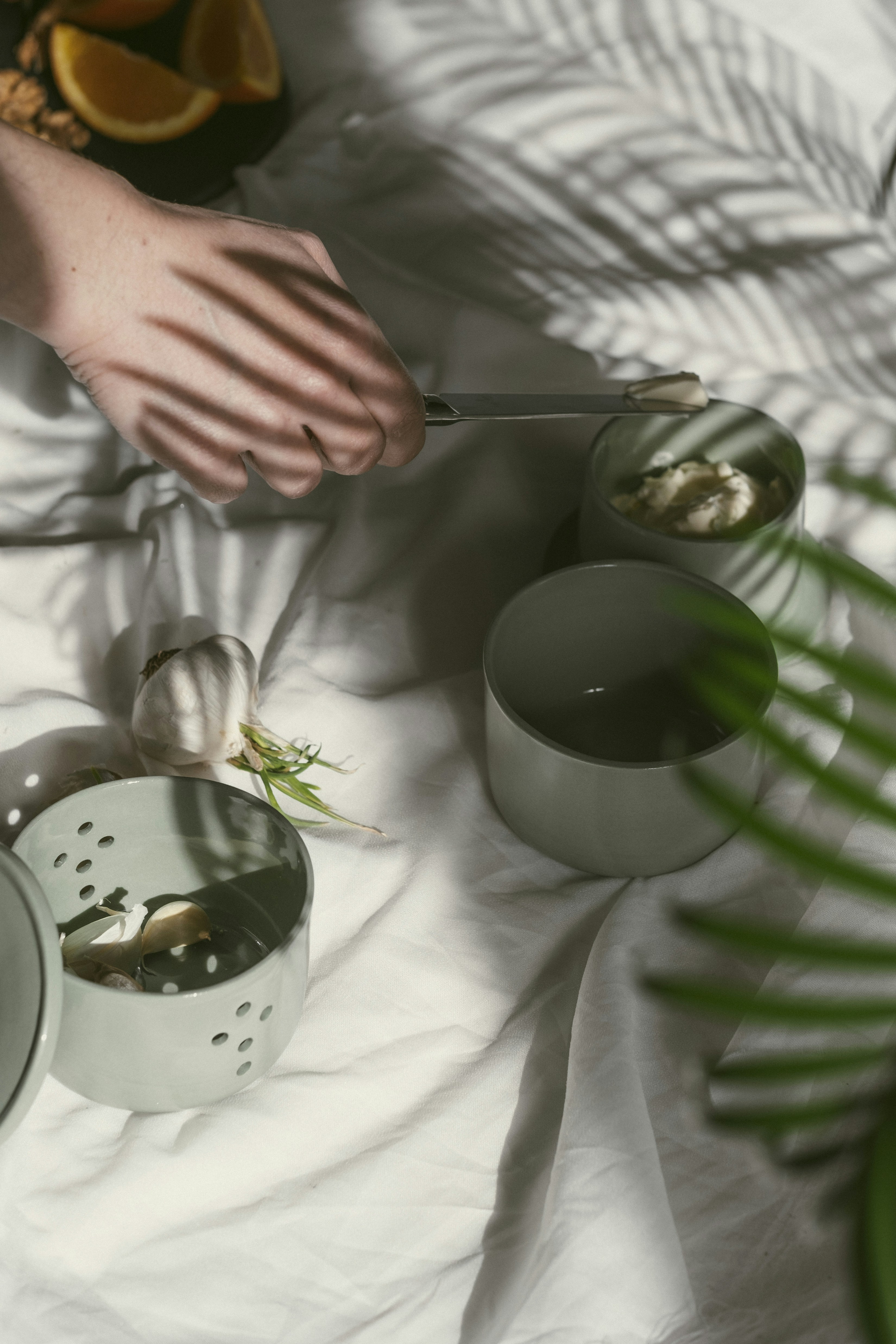 Shadowed Mise en Place: hand slicing citrus over sage-green ceramics