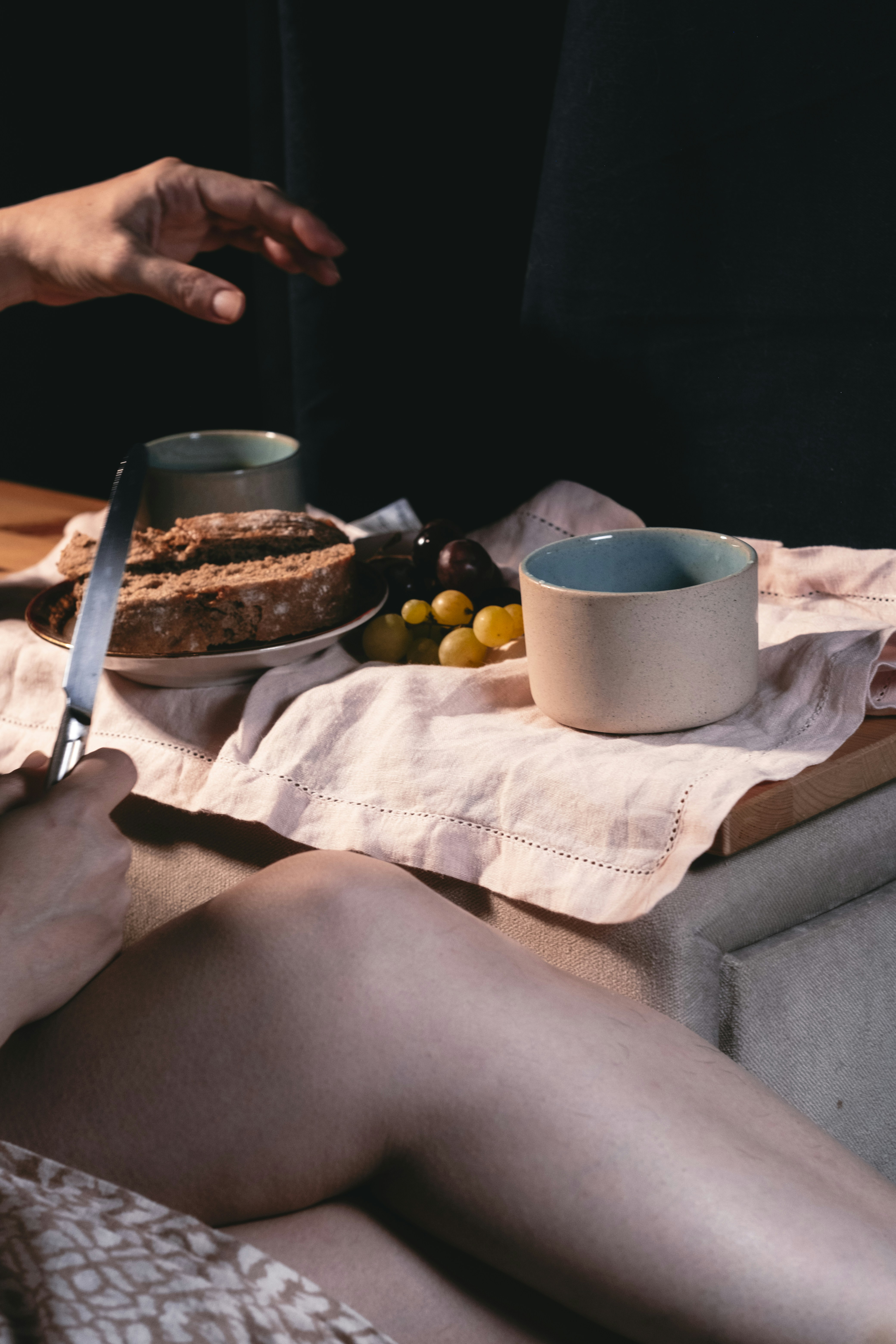 A Quiet Slice: Hands, Cake, and Grapes on Linen